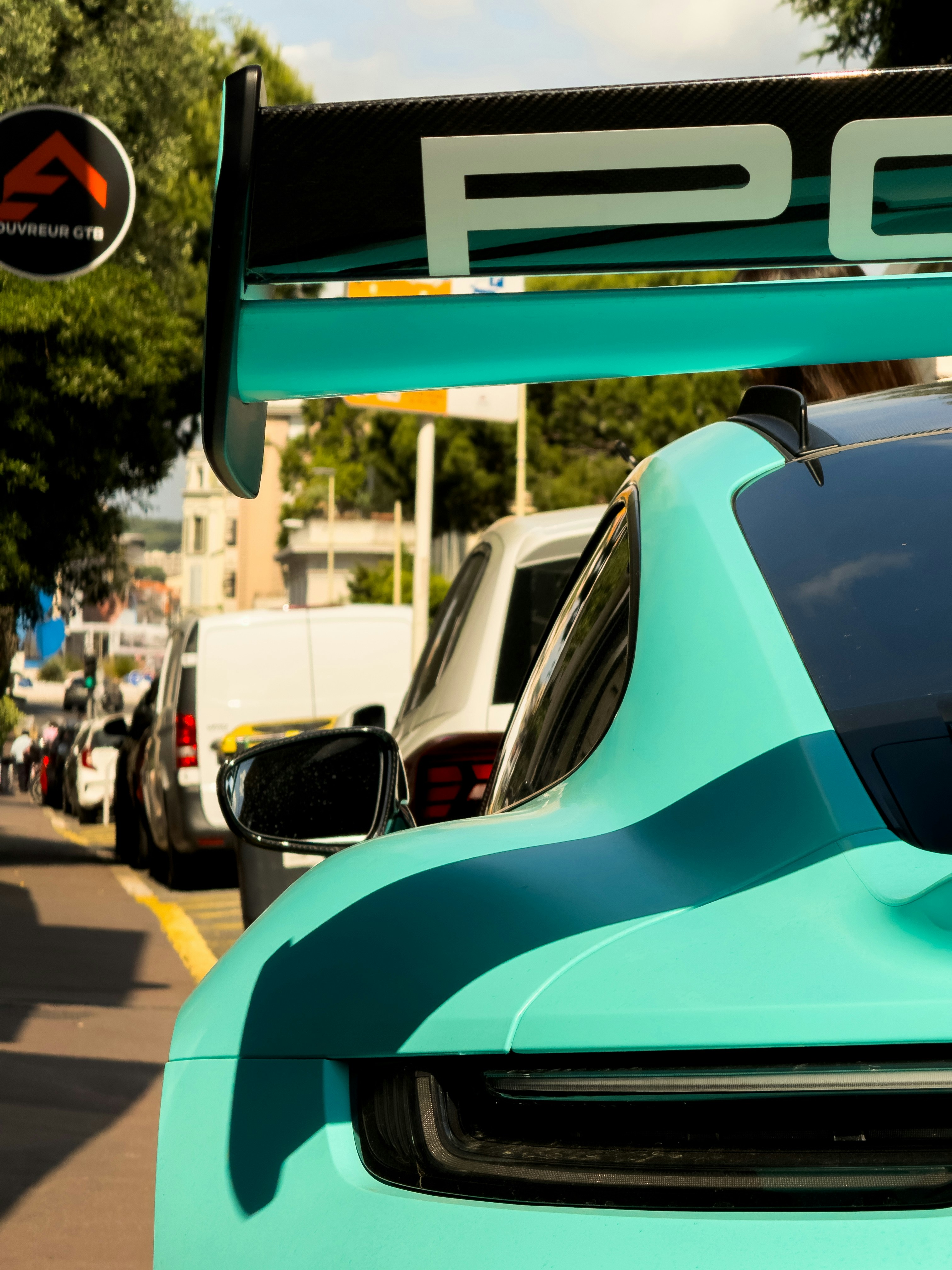 Minted Accent: A turquoise sports car at the curb with a dramatic rear wing
