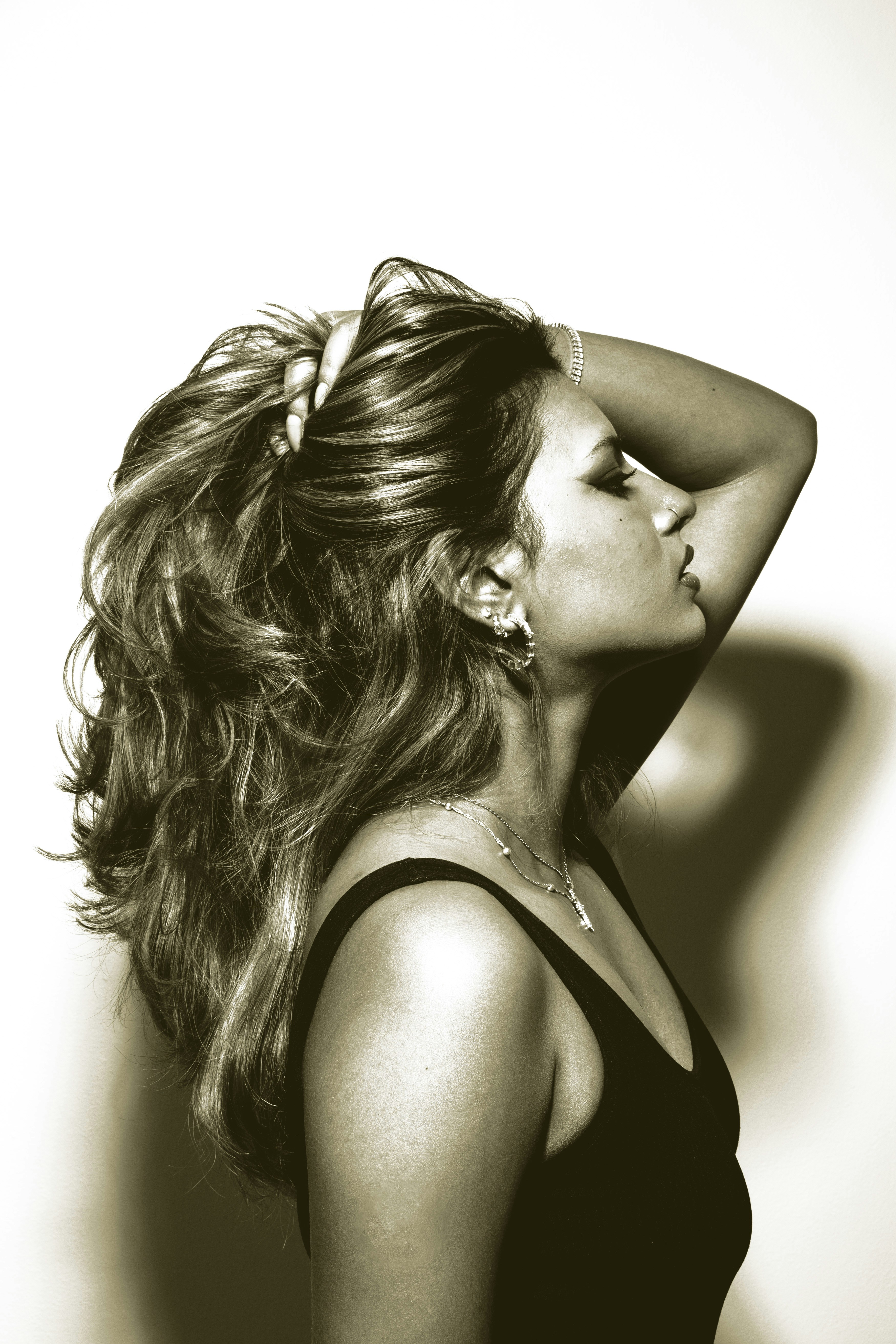 Profile portrait of a woman with voluminous hair, striking a graceful pose against a soft background.