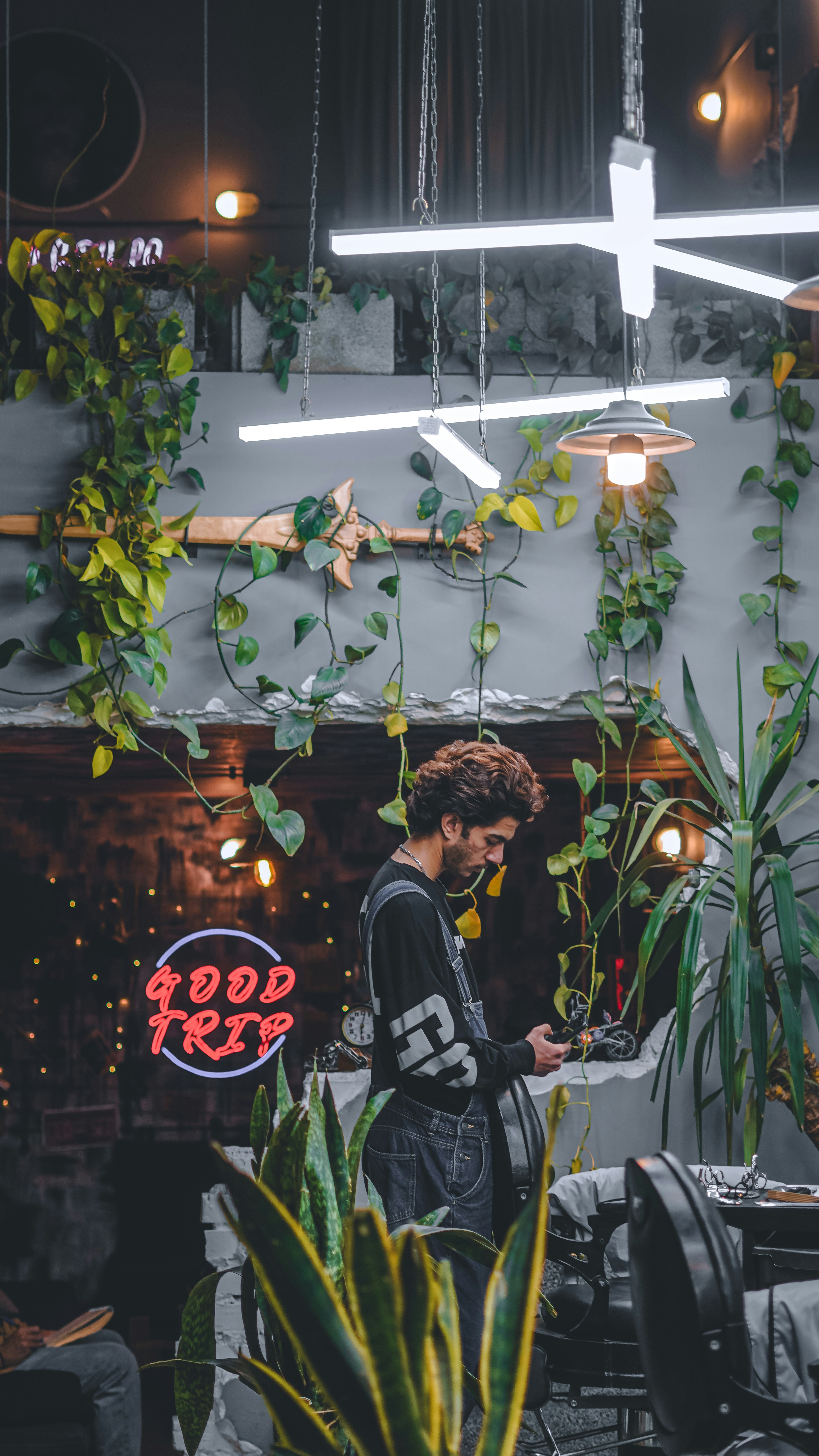 Neon, Foliage, and Focus: A Man in a Plant-Driven Café
