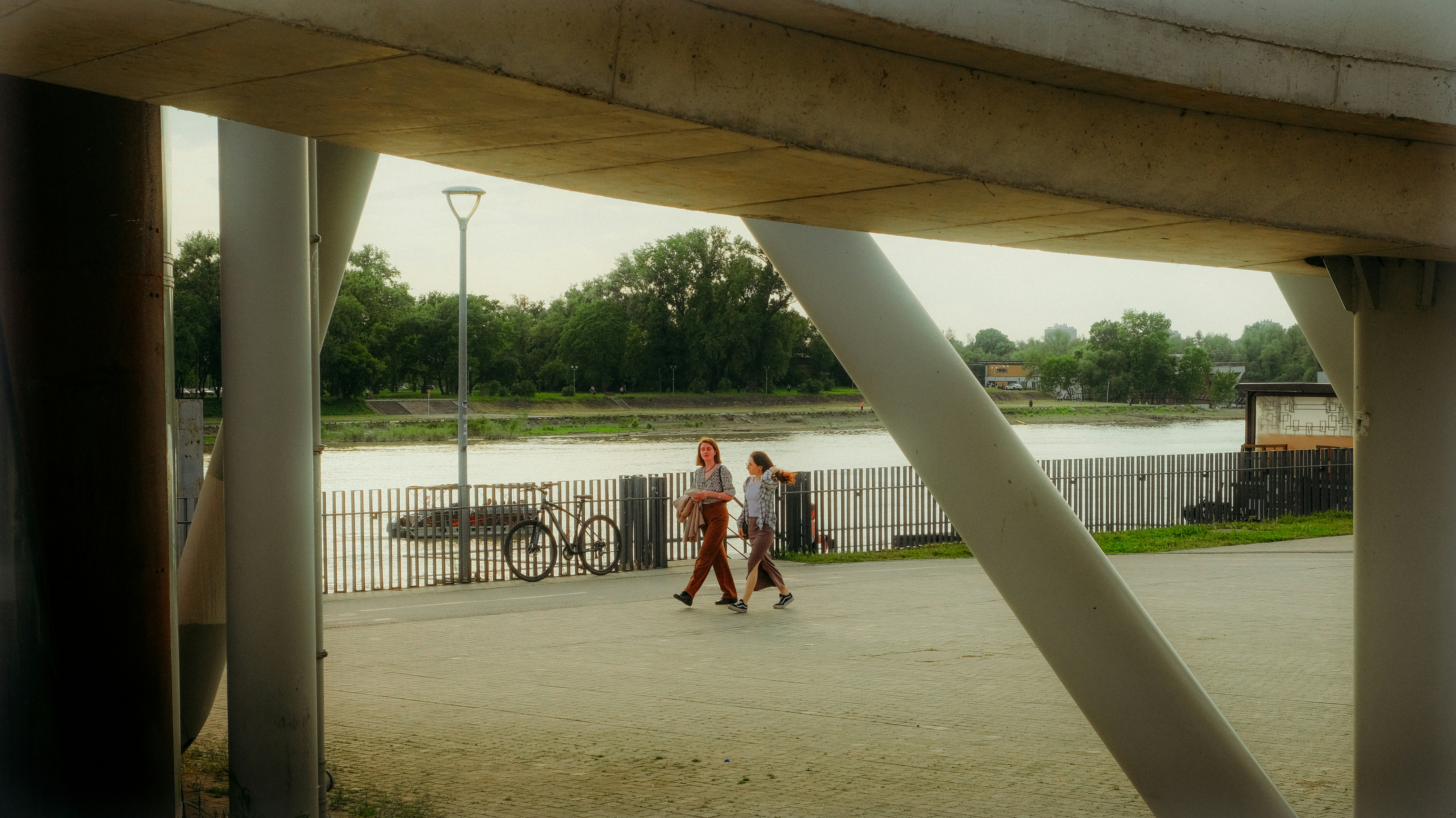 Riverside Stroll Framed by Diagonal Steel Arches