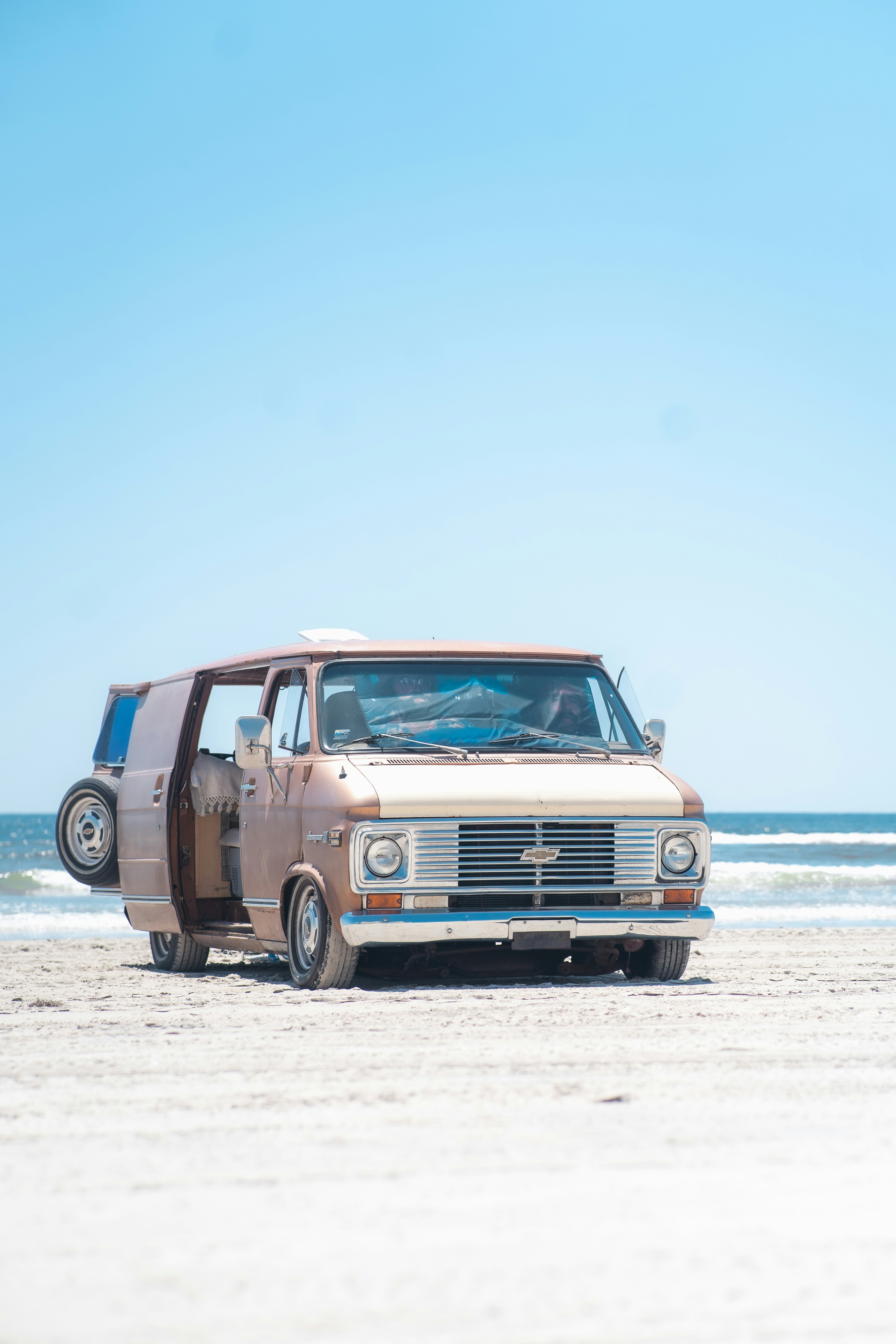 Dustyrusted van on a sunlit seaside road