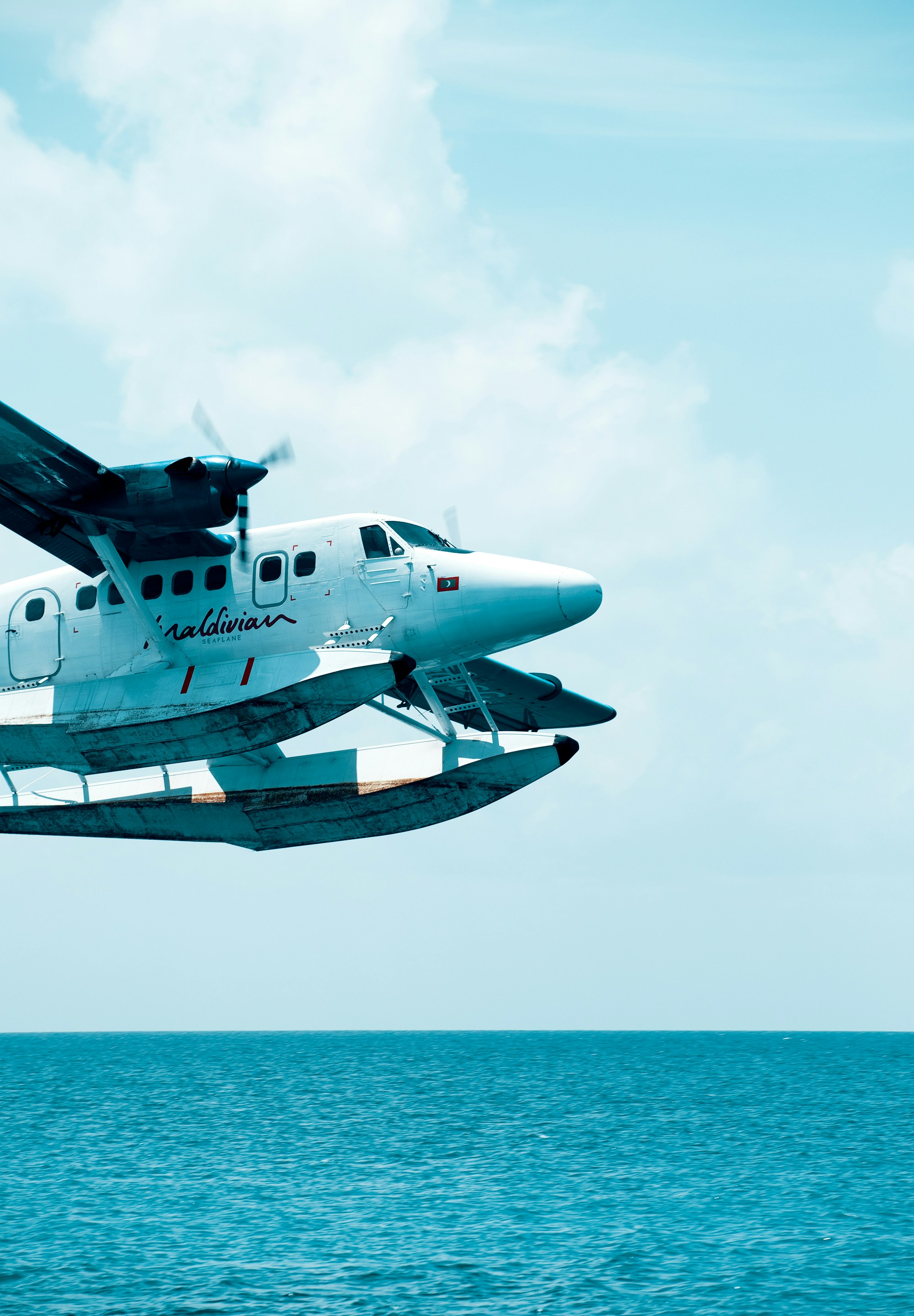 Seaplane flies over the clear, blue ocean. photo – Free Travel Image on ...