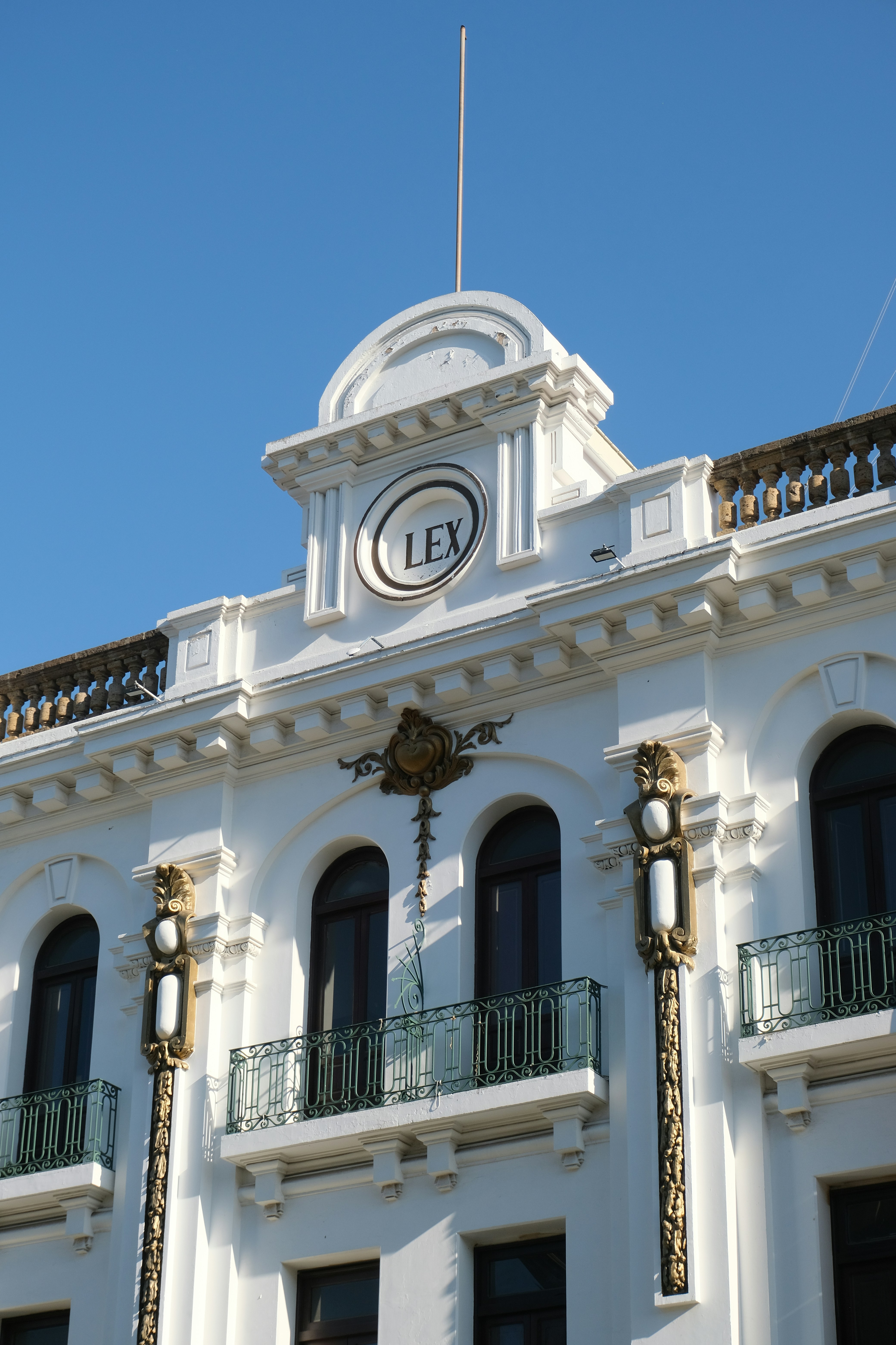 Historic building facade featuring ornate detailing and a prominent 'LEX' sign against a clear blue sky.