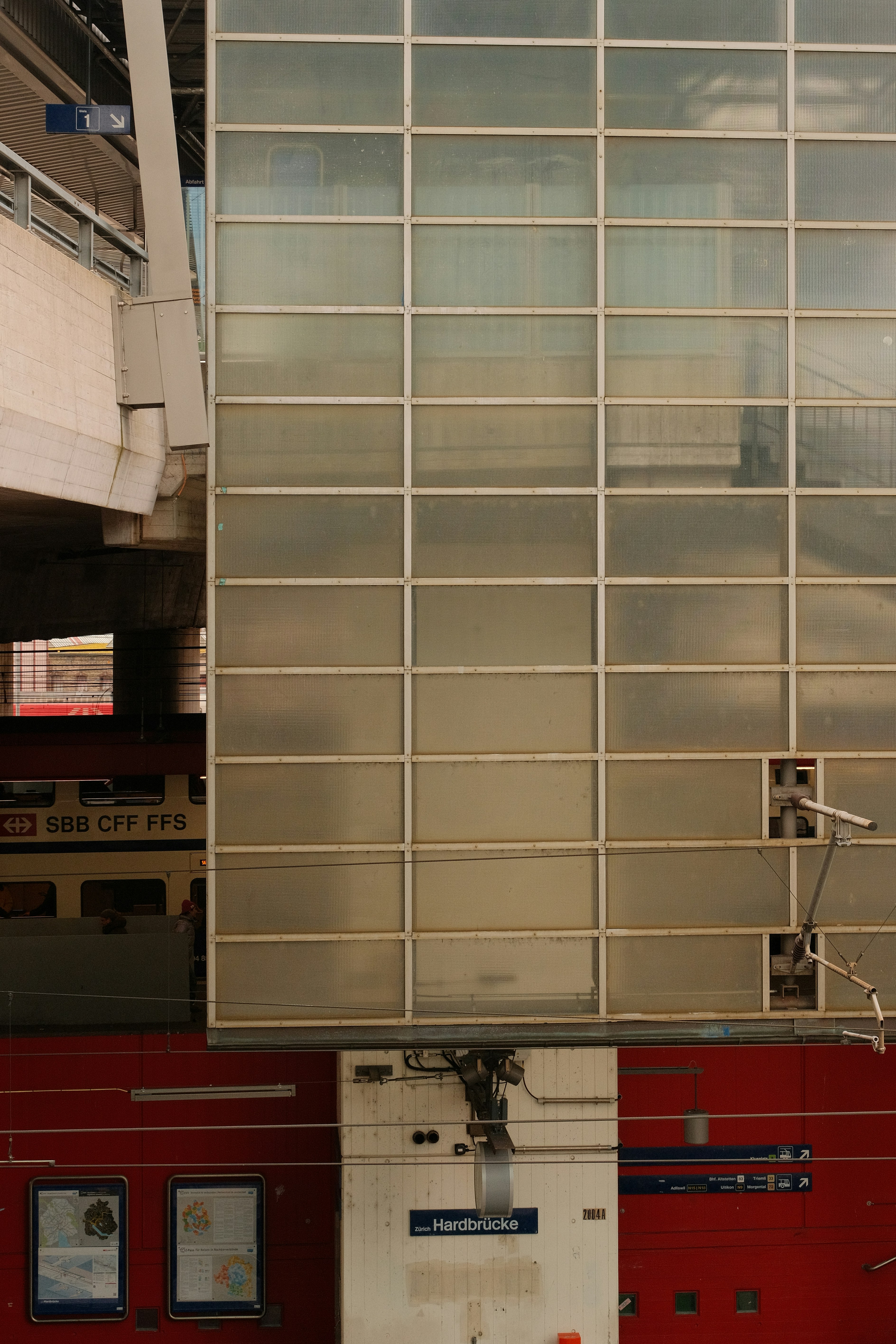 Glass-Grid Facade Framing a Red Train at Hardbrücke Station