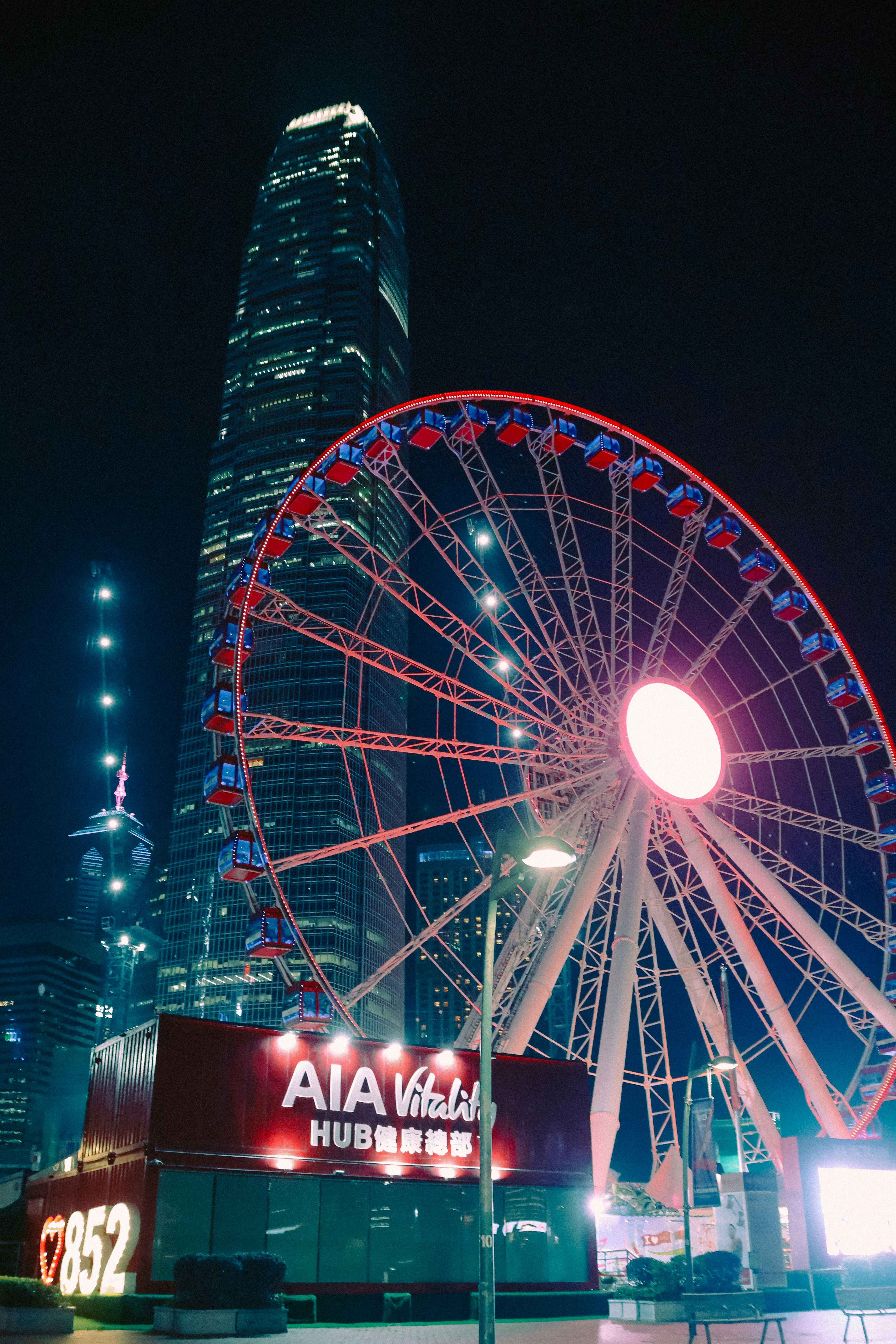 Neon Wheel of the Harbor: Night Lights Beyond a Skyscraper