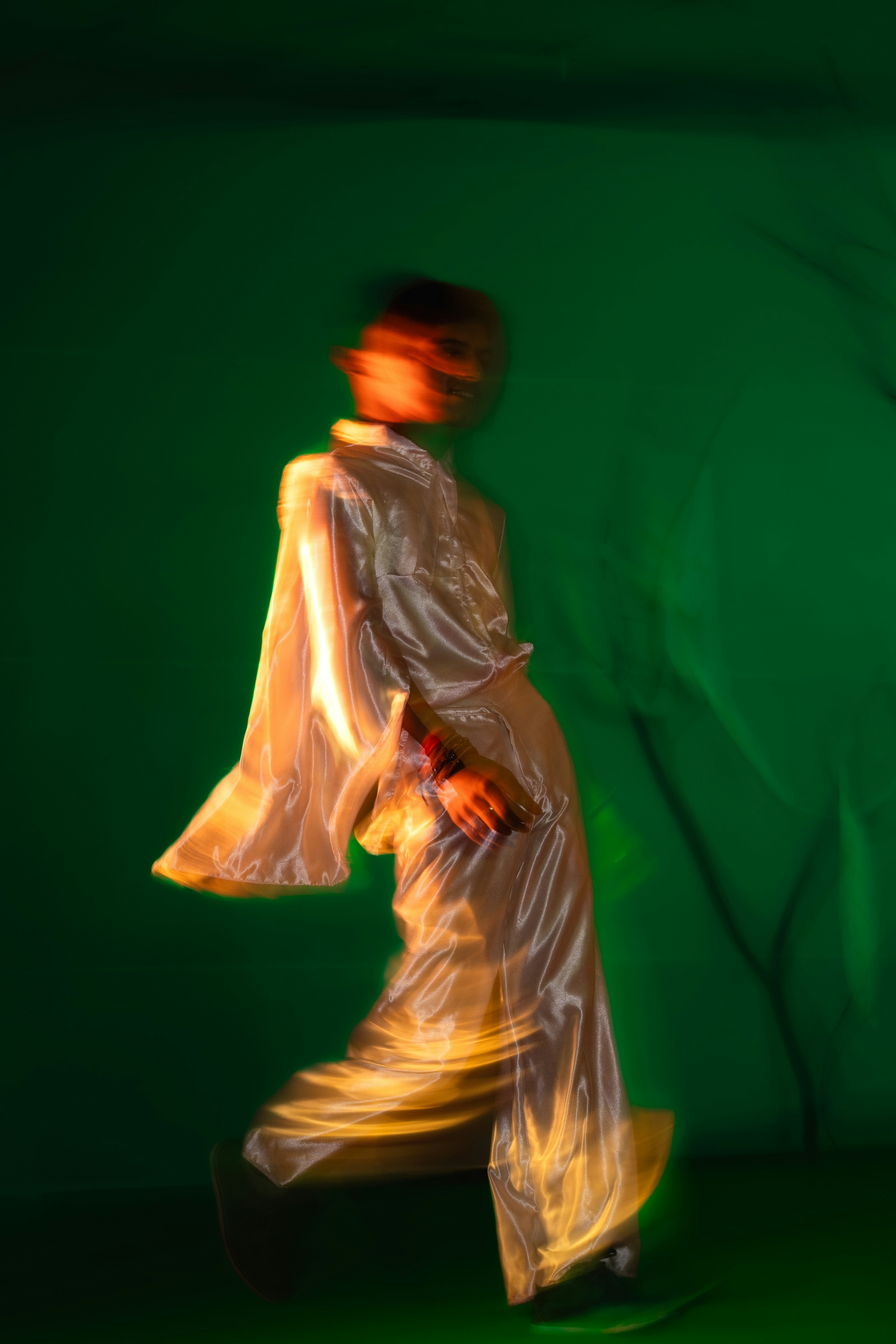 A blurred figure in white against a green backdrop.