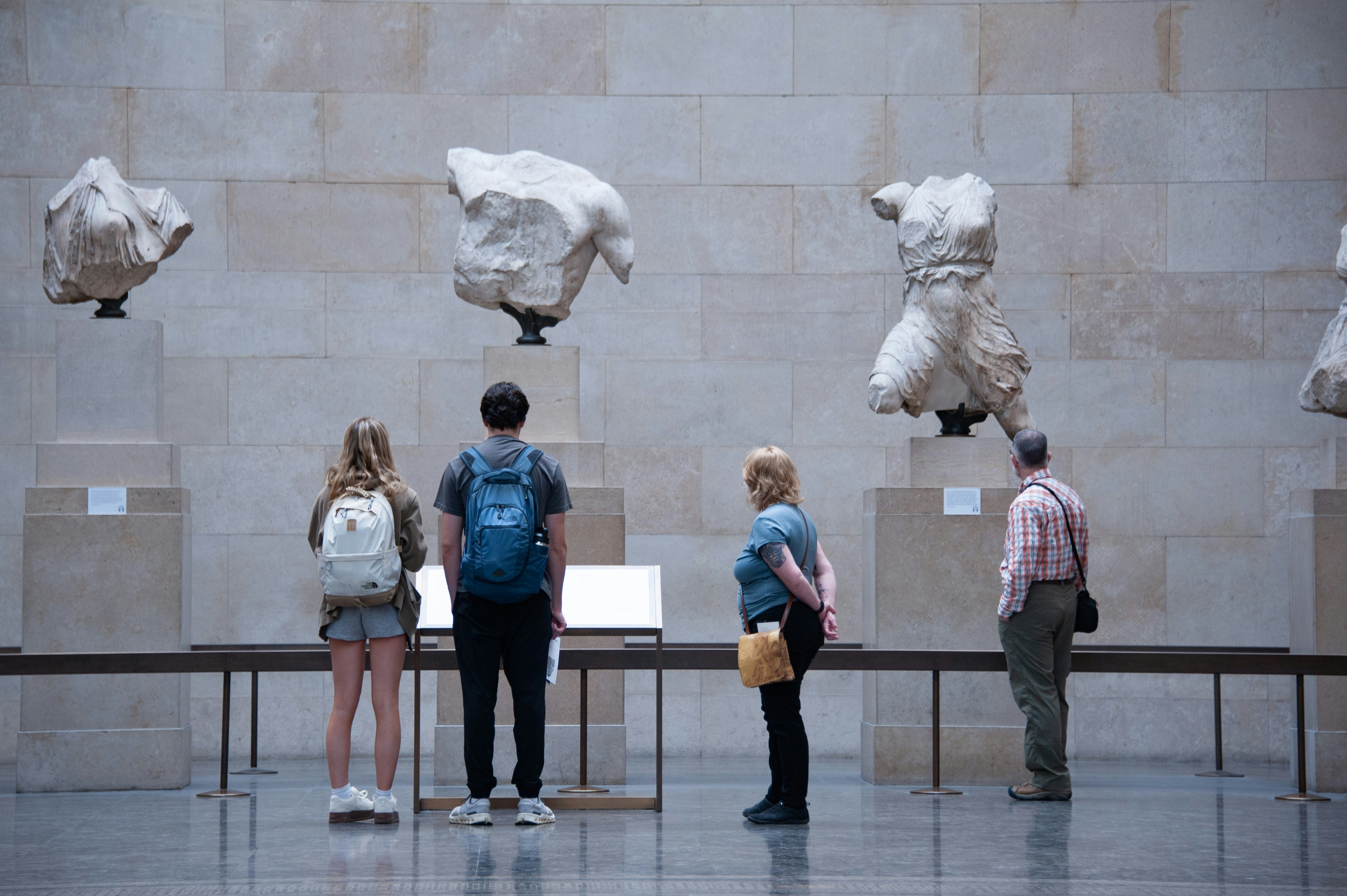 Quiet Gallery Moment: Visitors Observe Classical Sculptures in a Modern Museum