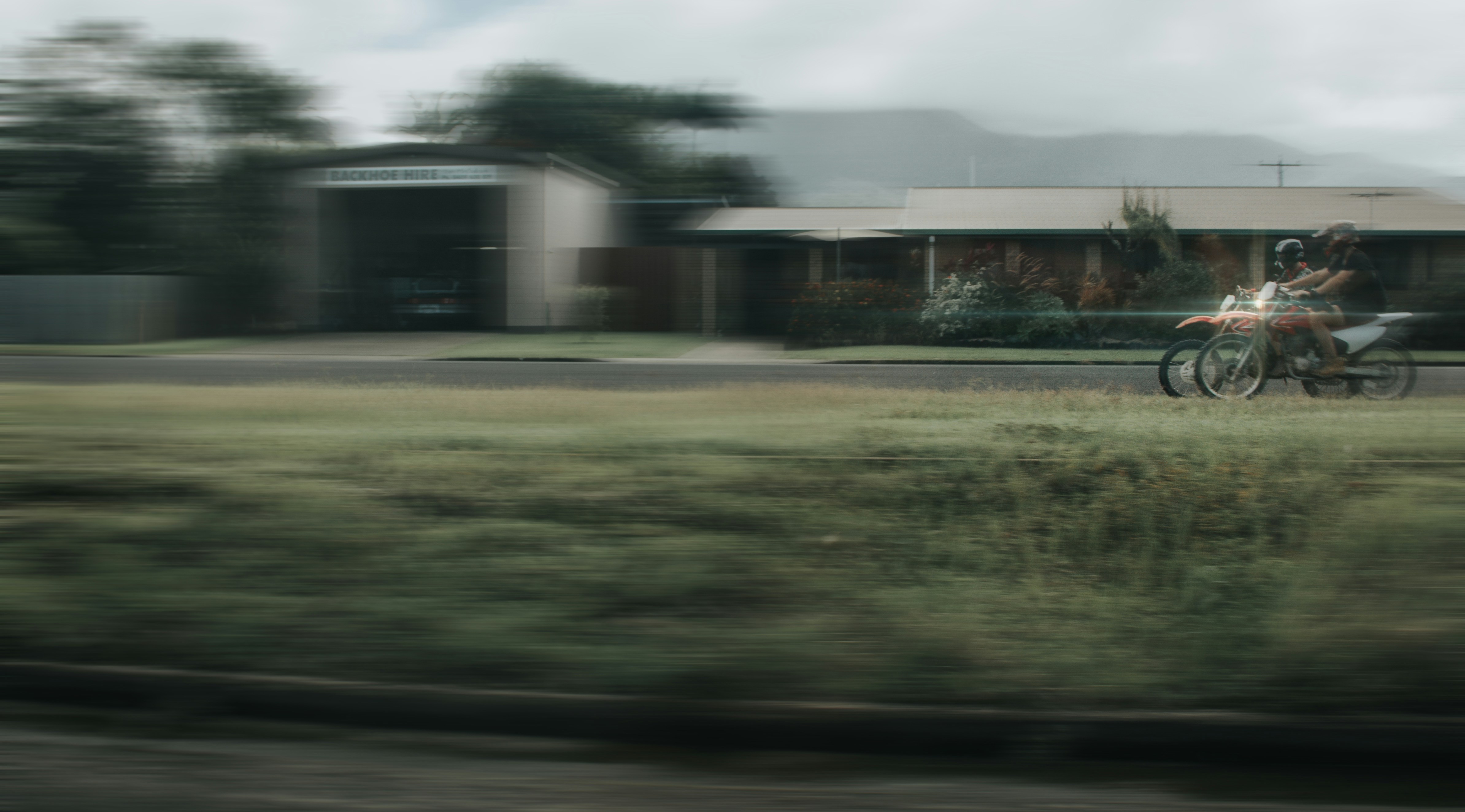 Suburban Blur: A Motorcycle Rider Drifts Across a Quiet Street