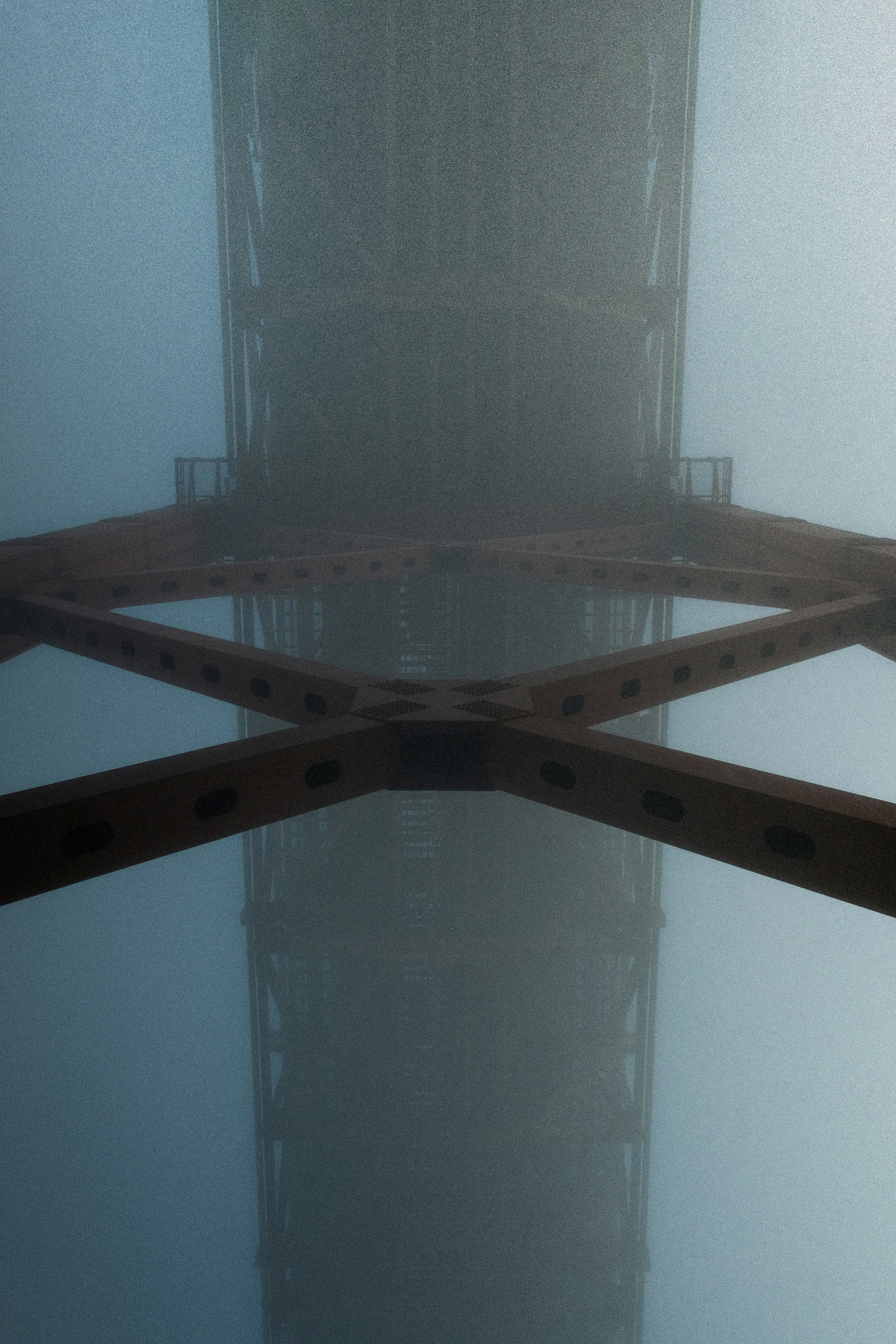 Under the Blue Mist: Rusted Trusses Framing a Fogged Bridge