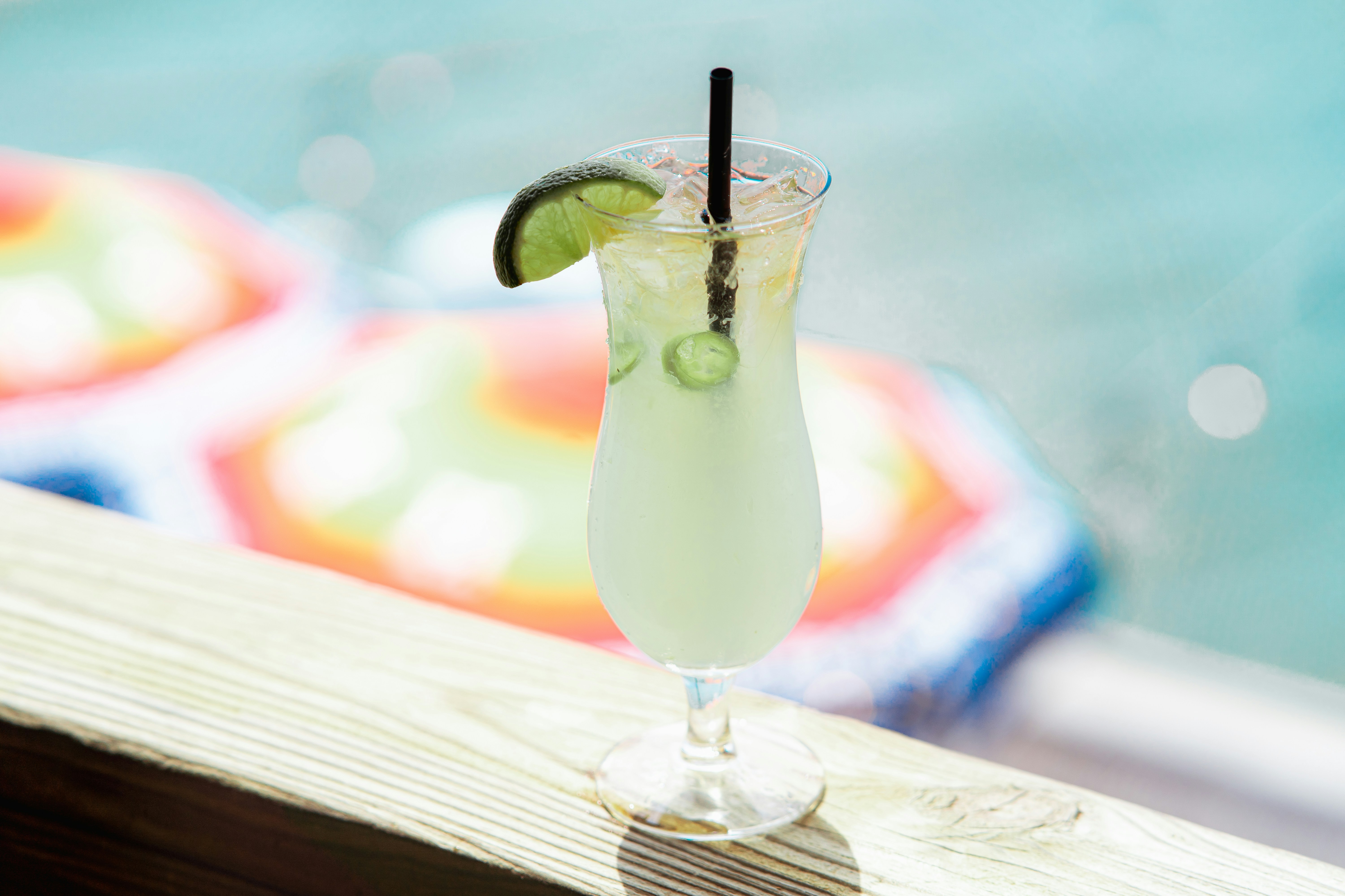 Poolside Glow: A Lime-Garnished Cocktail Framed by Turquoise Blur