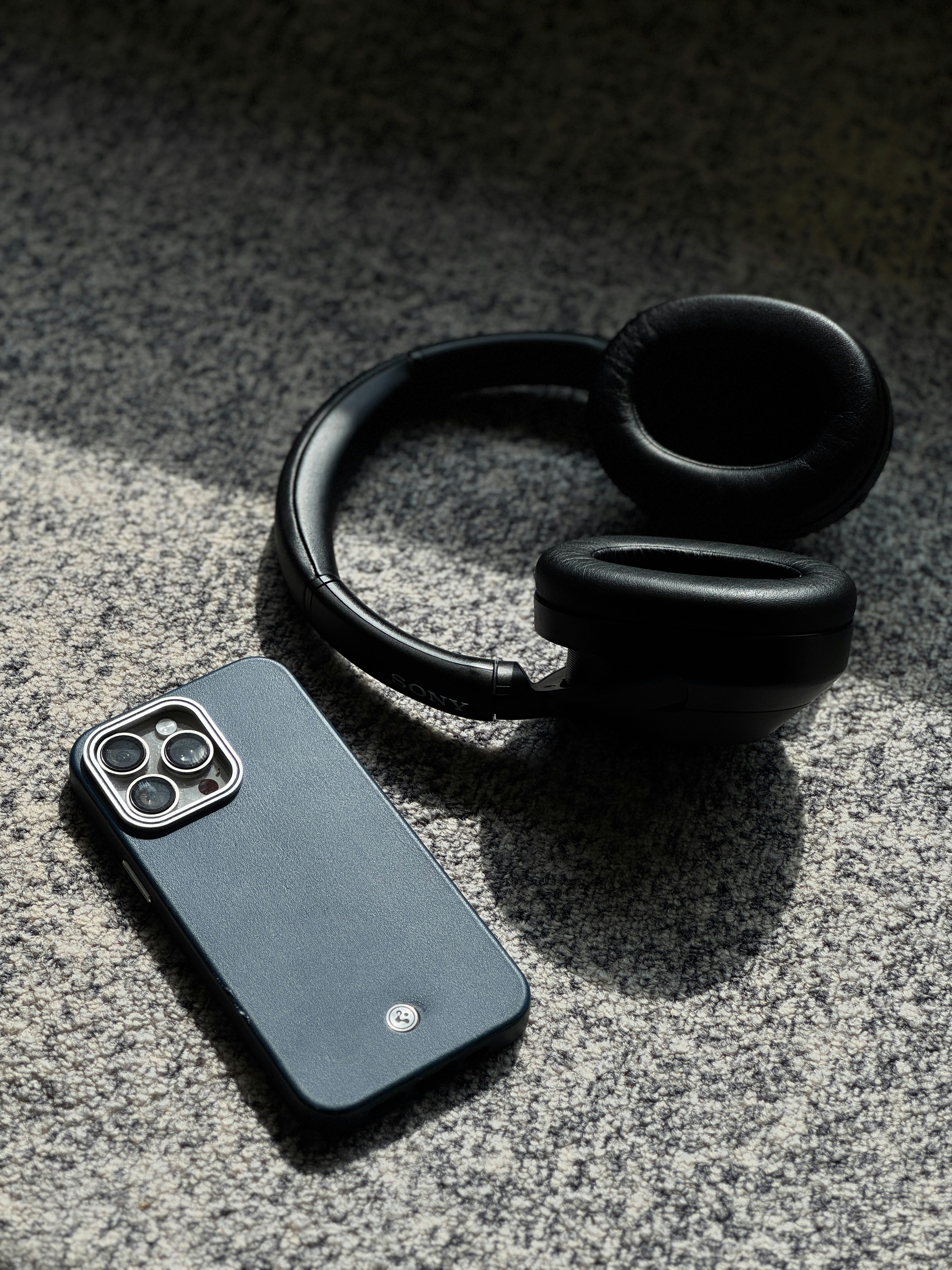 Phone and headphones sit on a carpeted surface.