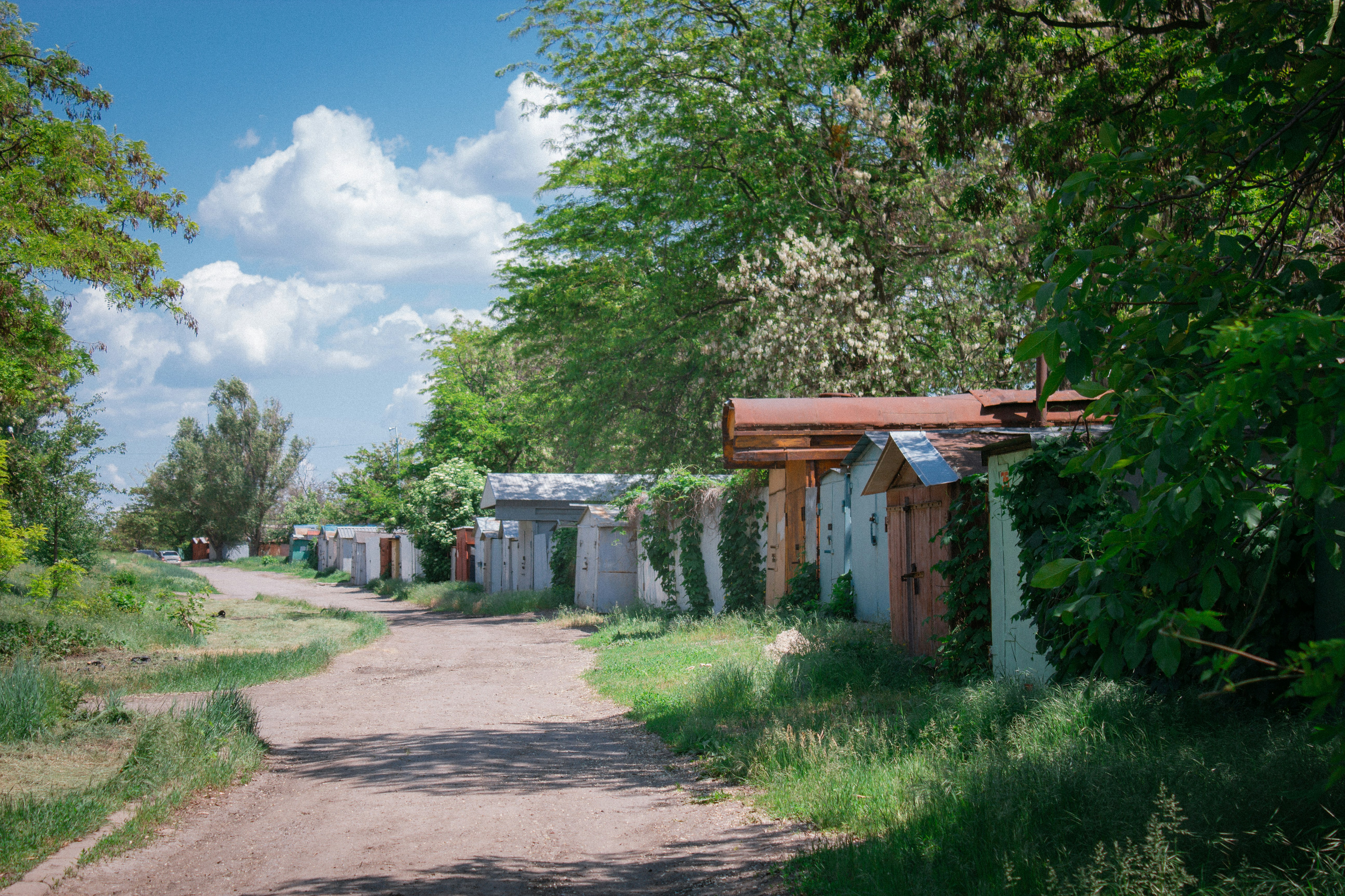 Row of weathered garages lining a sunlit rural lane