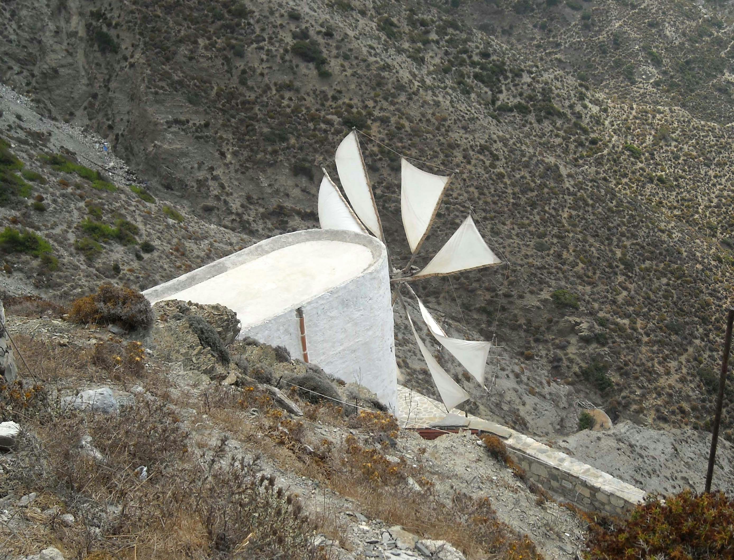 Silent Sails: A hillside wind-rotor sculpture amid rugged terrain