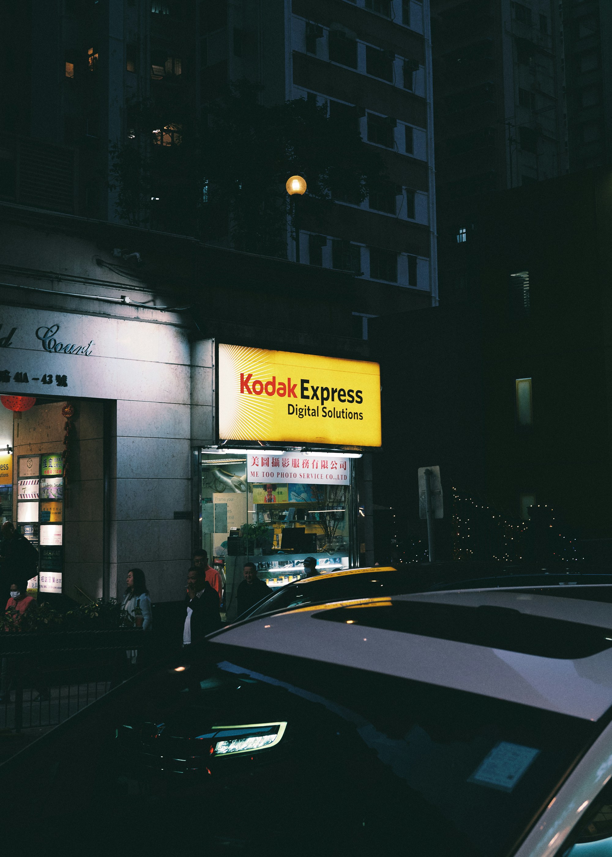 A kodak express sign illuminates a dark street.