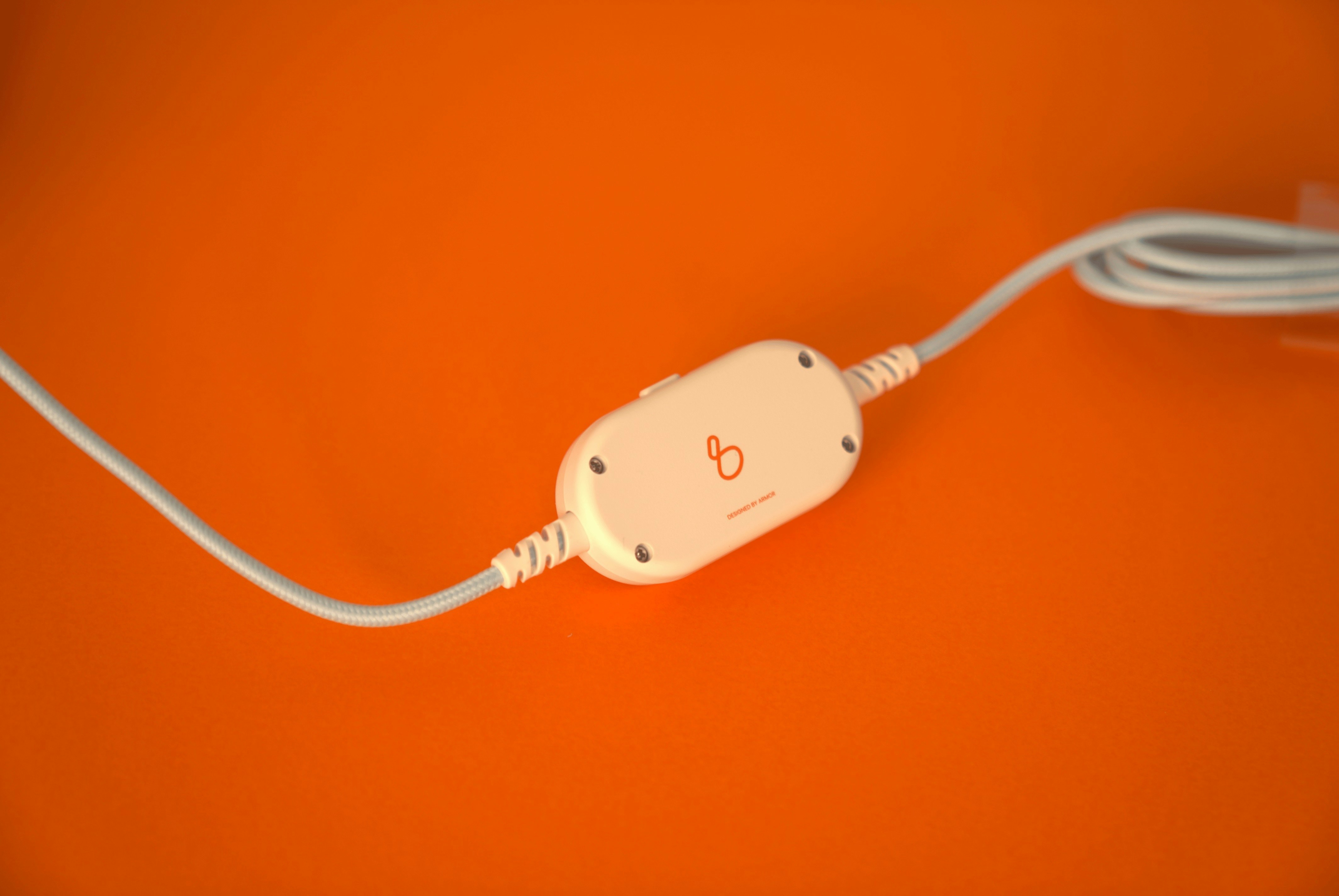 A white power adapter lies on an orange surface. photo – Free India ...