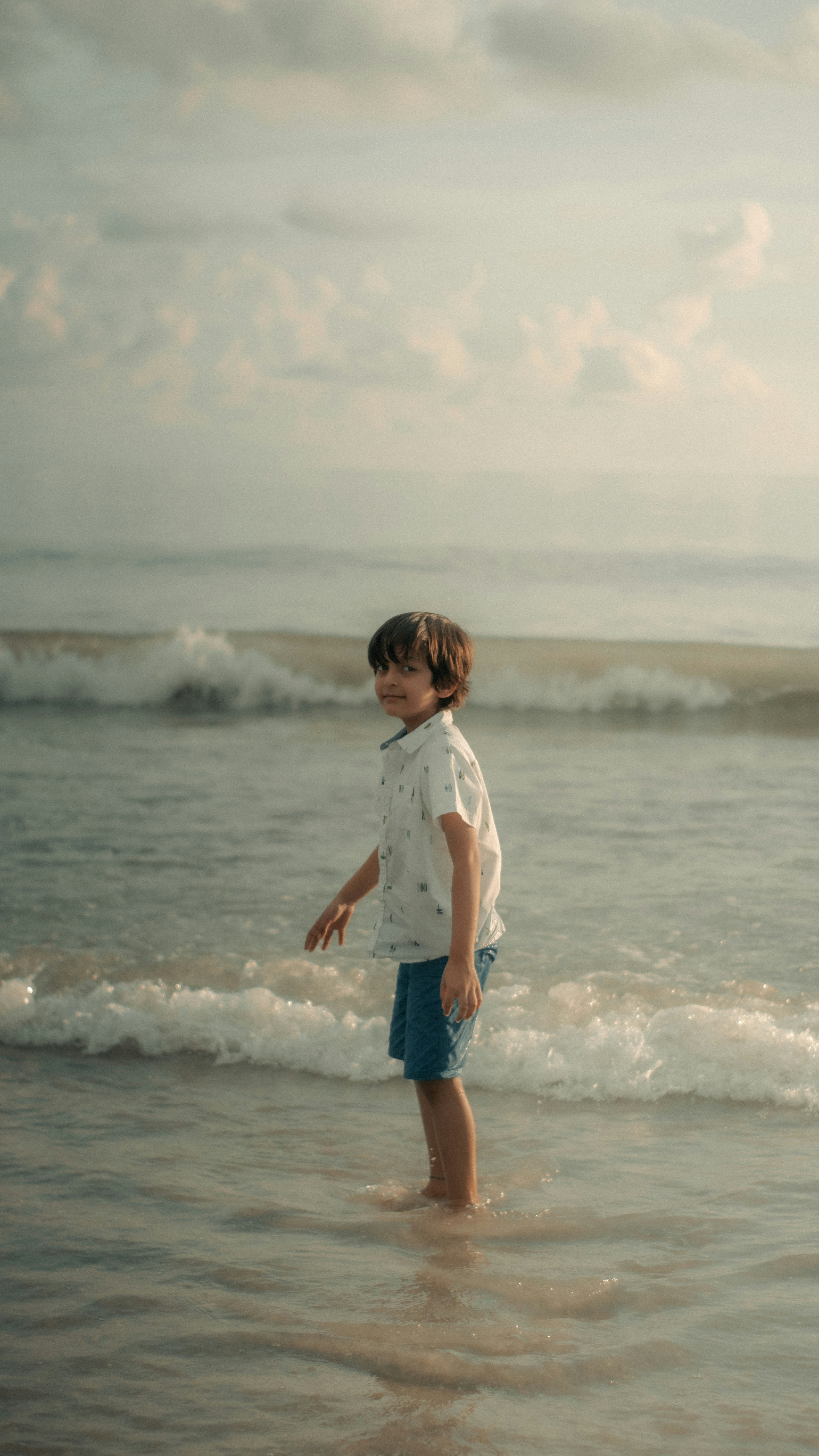 A boy stands in the ocean, smiling. photo – Free Beach Image on Unsplash