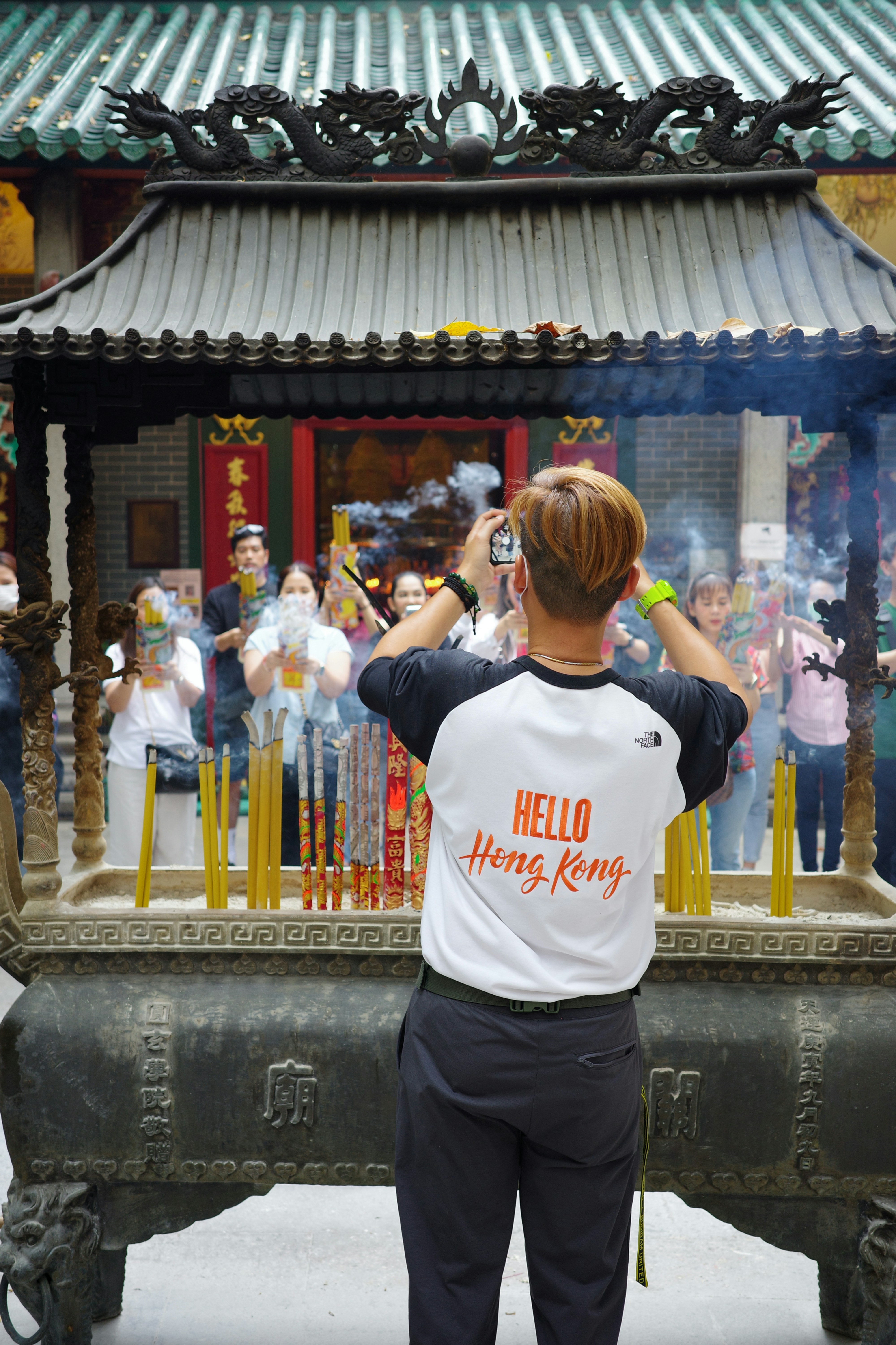 Man photographs worshippers at a hong kong temple.