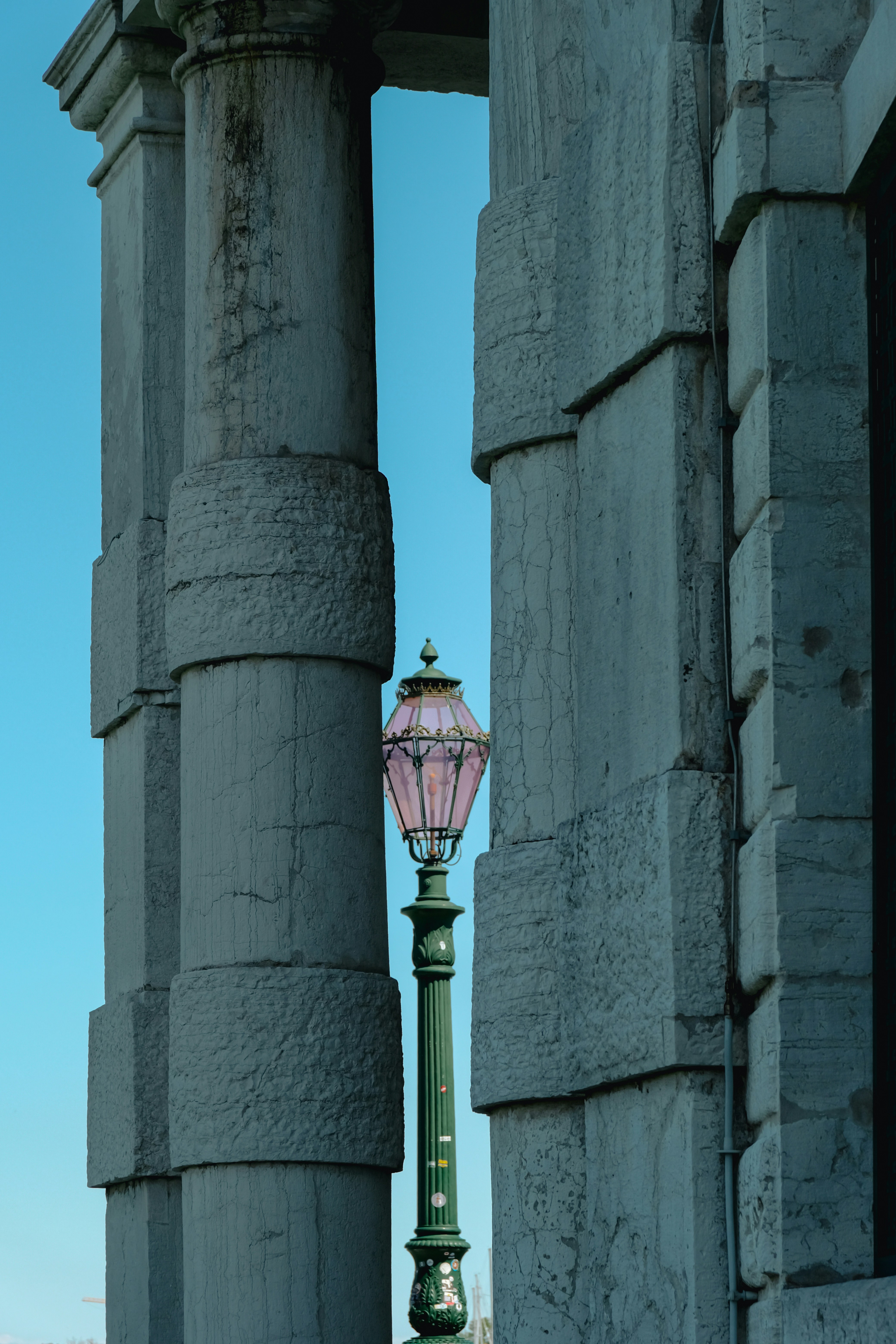 A pink lamp post is framed by columns. photo – Free Building Image on ...