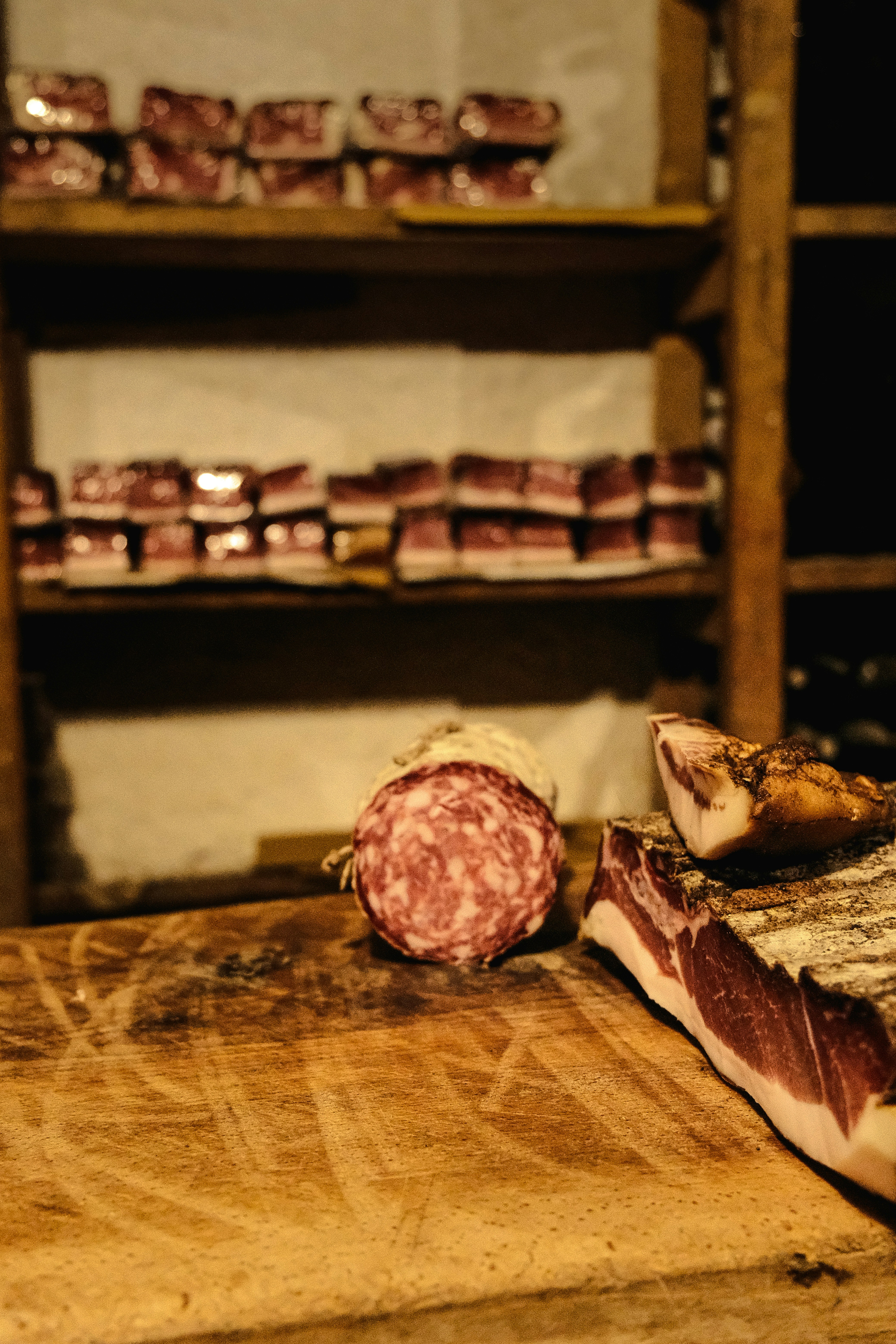 Amber Ledger: Salami on Weathered Wood Beneath Deli Light