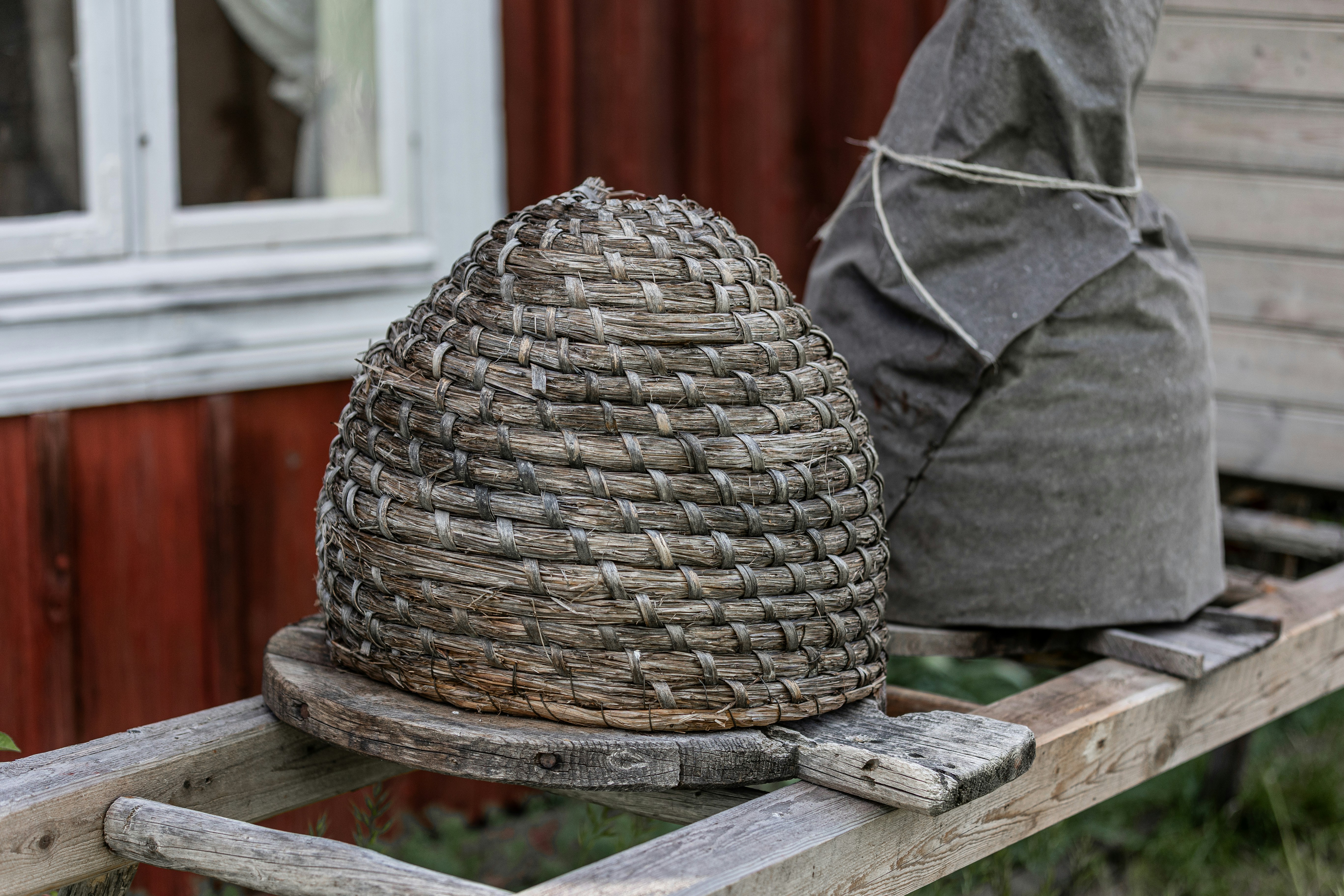 Beehives are shown outside a red-painted building. photo – Free Window ...