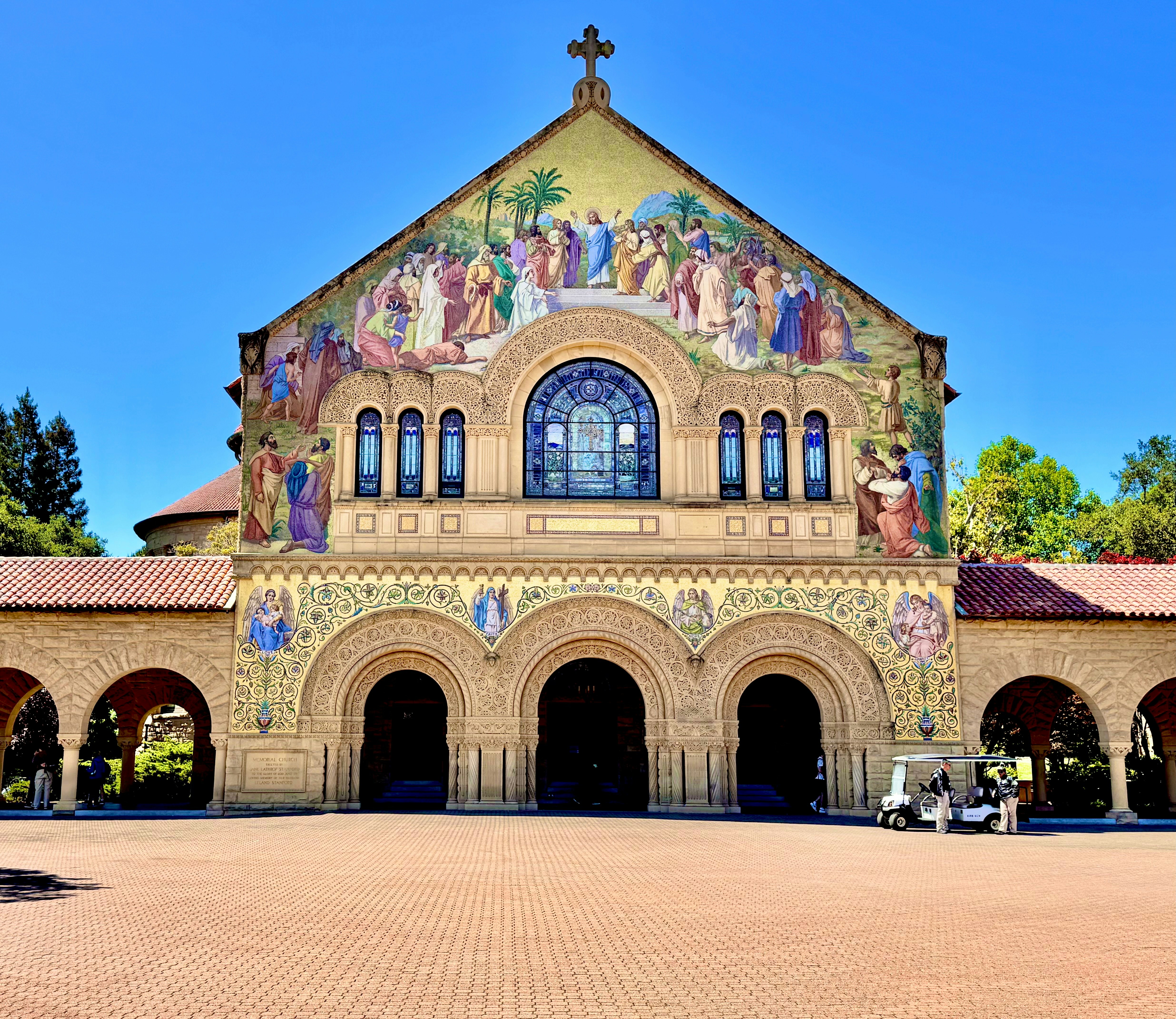 Intricate mural adorning the façade of a historic building, showcasing religious figures and scenes beneath a clear blue sky.