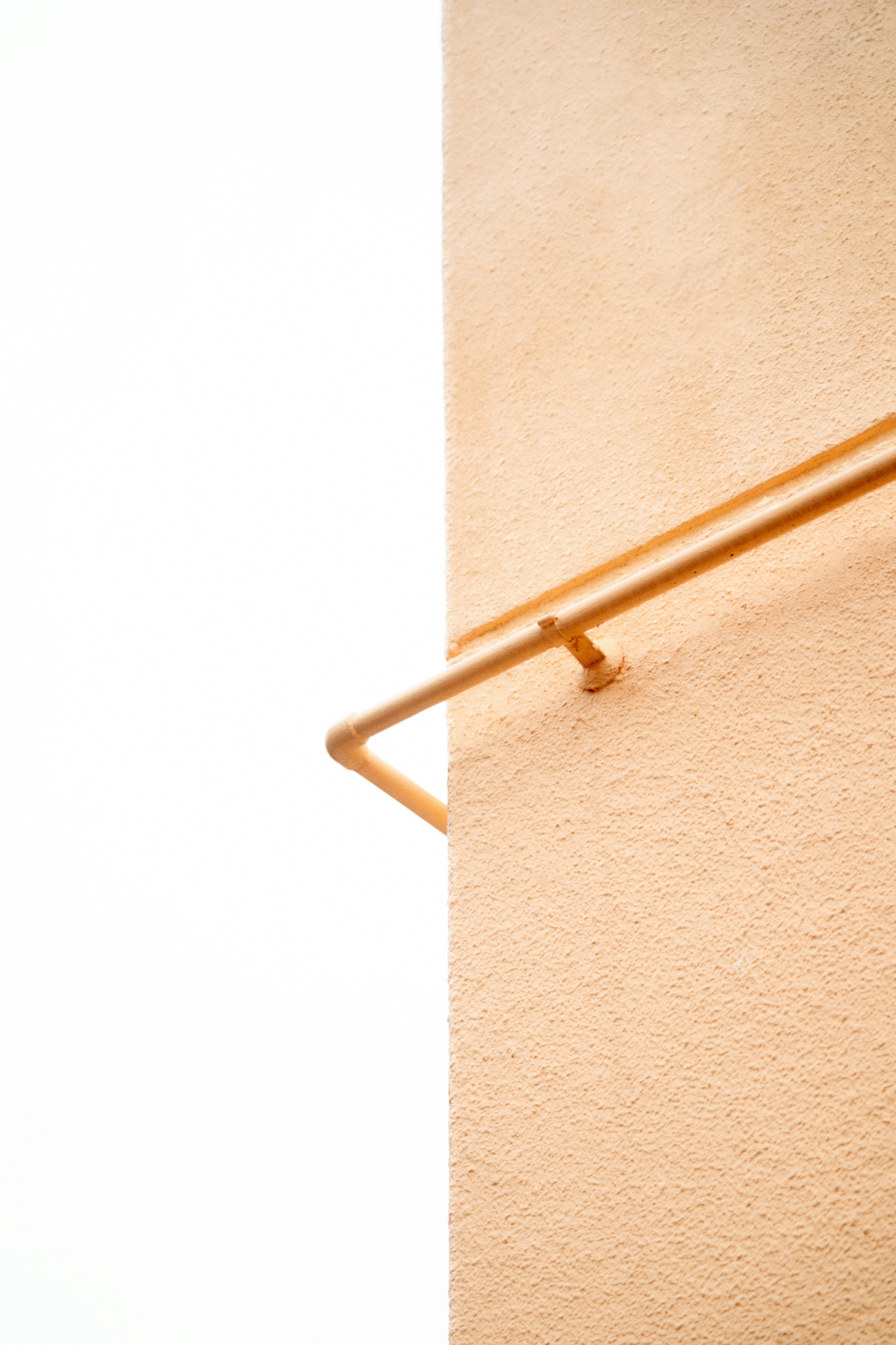 A handrail is attached to a peach colored wall.