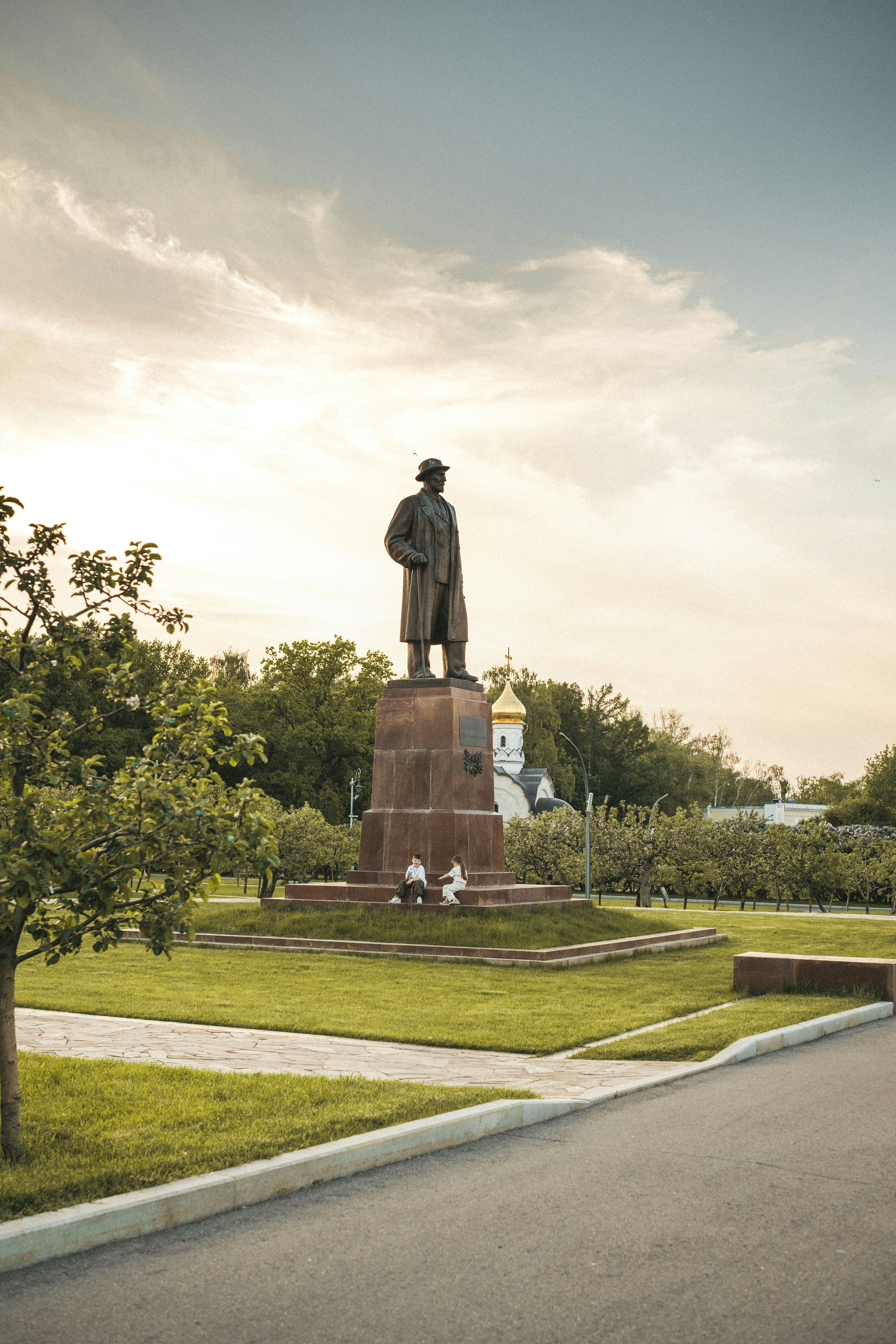 Dusk Sentinel: A Bronze Figure Standing in a Serene Park at Sunset