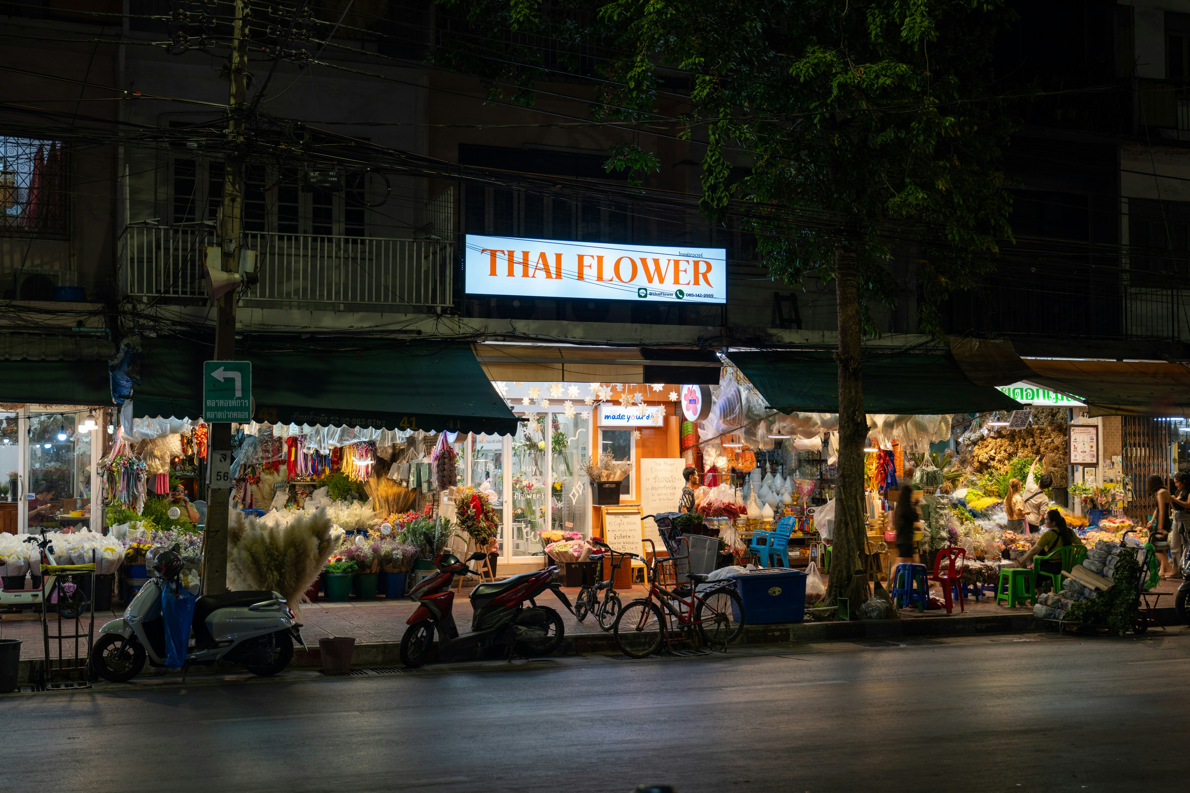 Midnight Bloom: Thai Flower Shop's Warm Halo on a Bustling Street