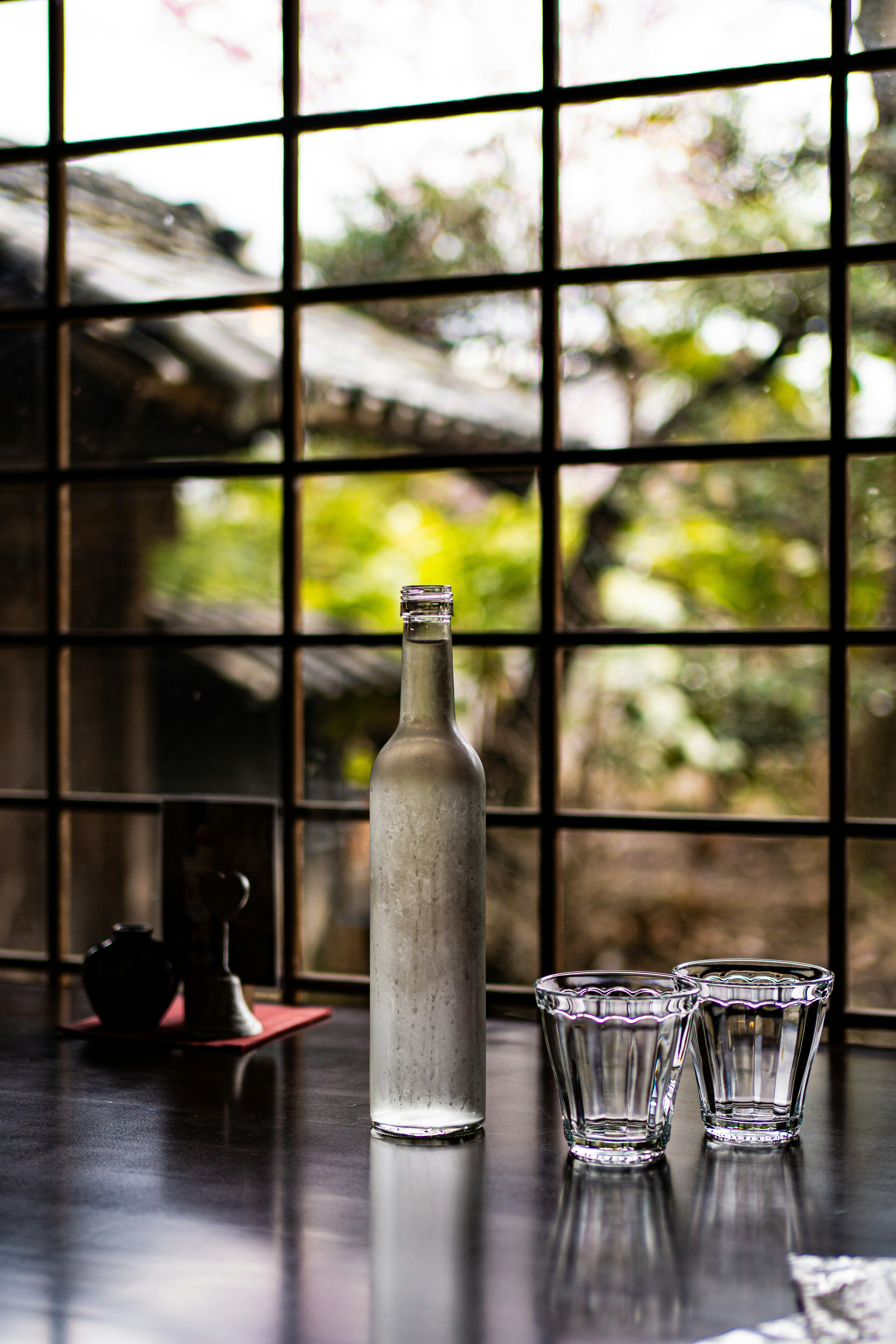 Frosted Bottle and Twin Glasses Framed by a Lattice Window