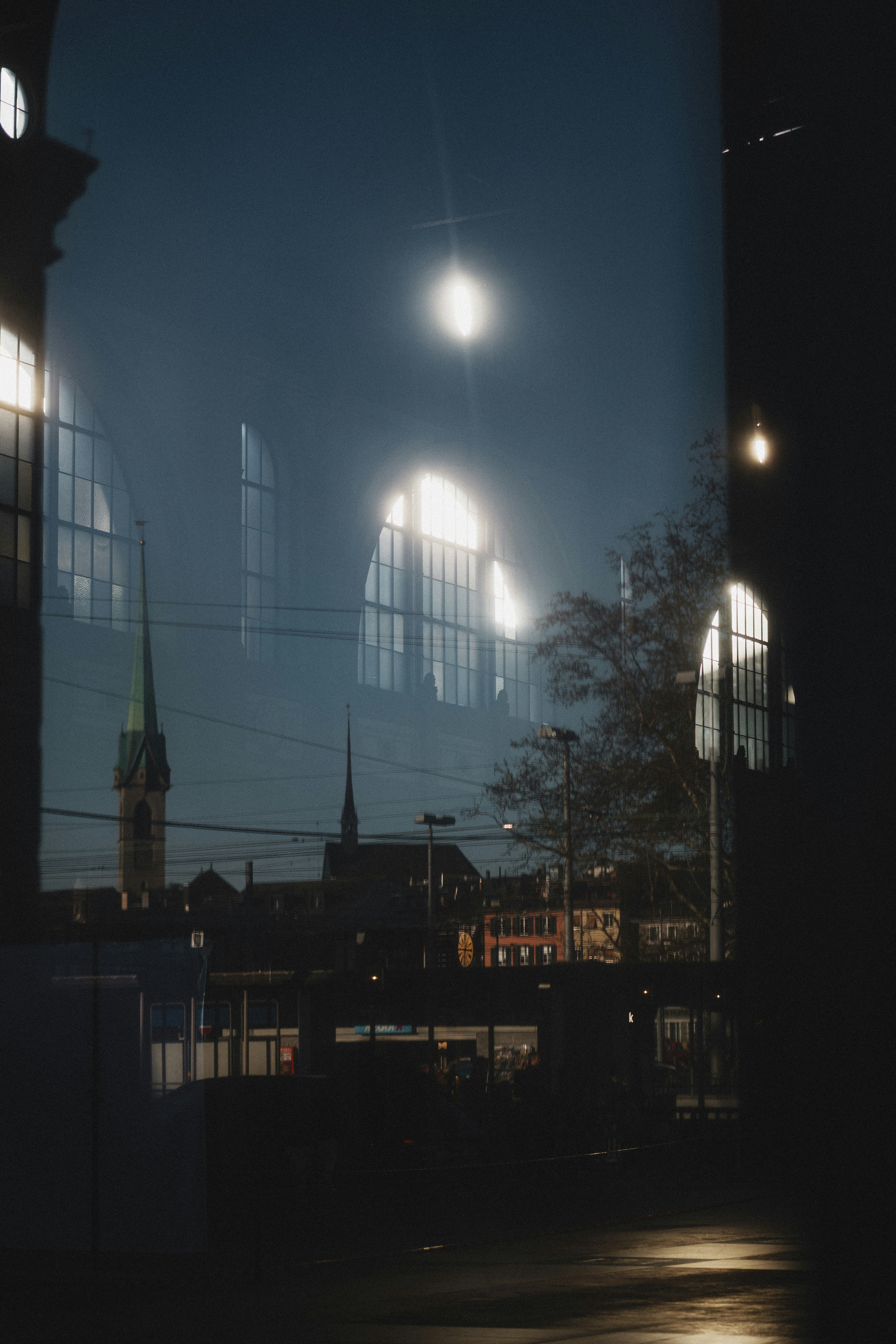 City lights reflect in a window at dusk.