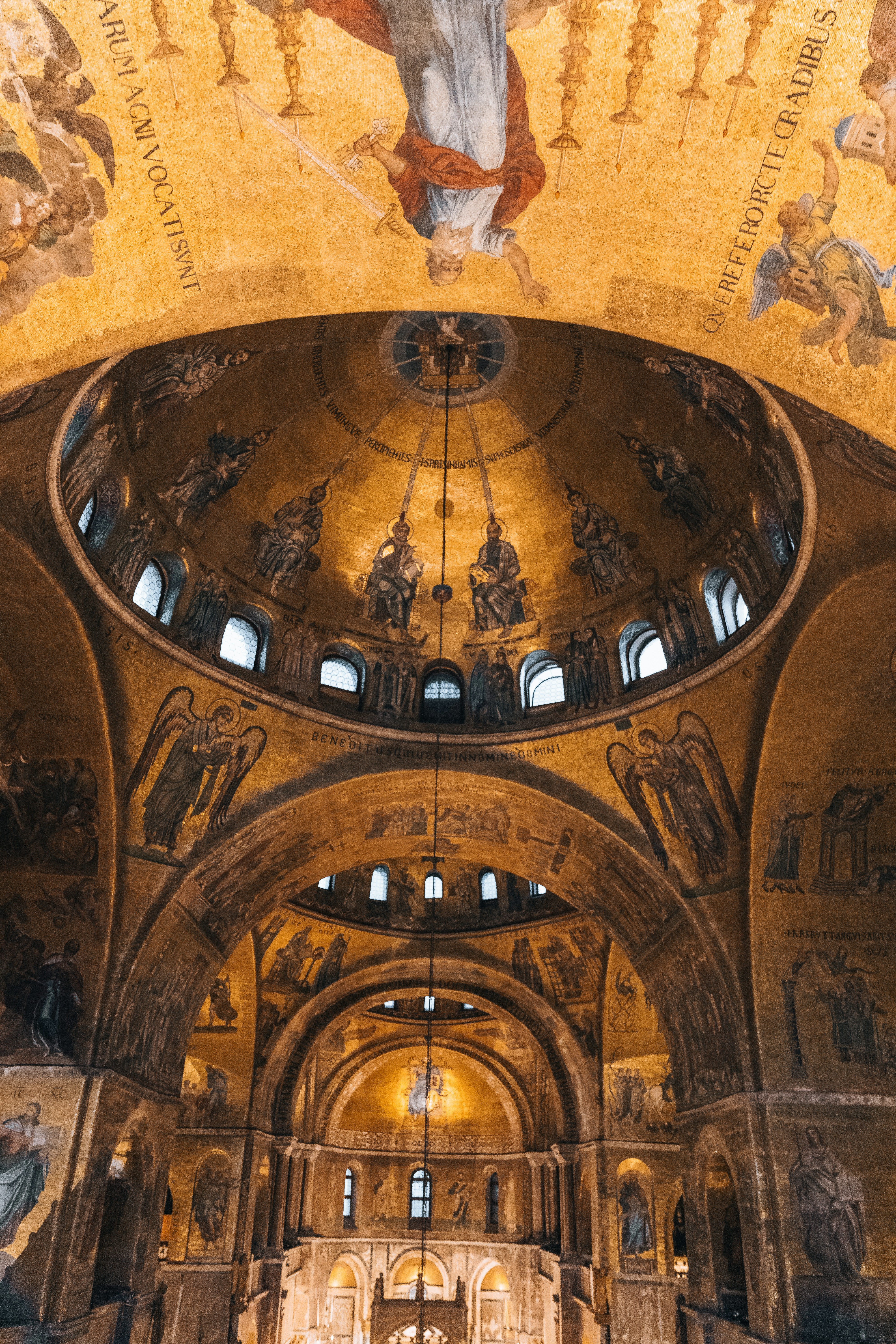 Intricate mosaics adorn the dome of a historic cathedral, showcasing divine figures and celestial motifs. The warm glow of the gold leaf enhances the spiritual ambiance.