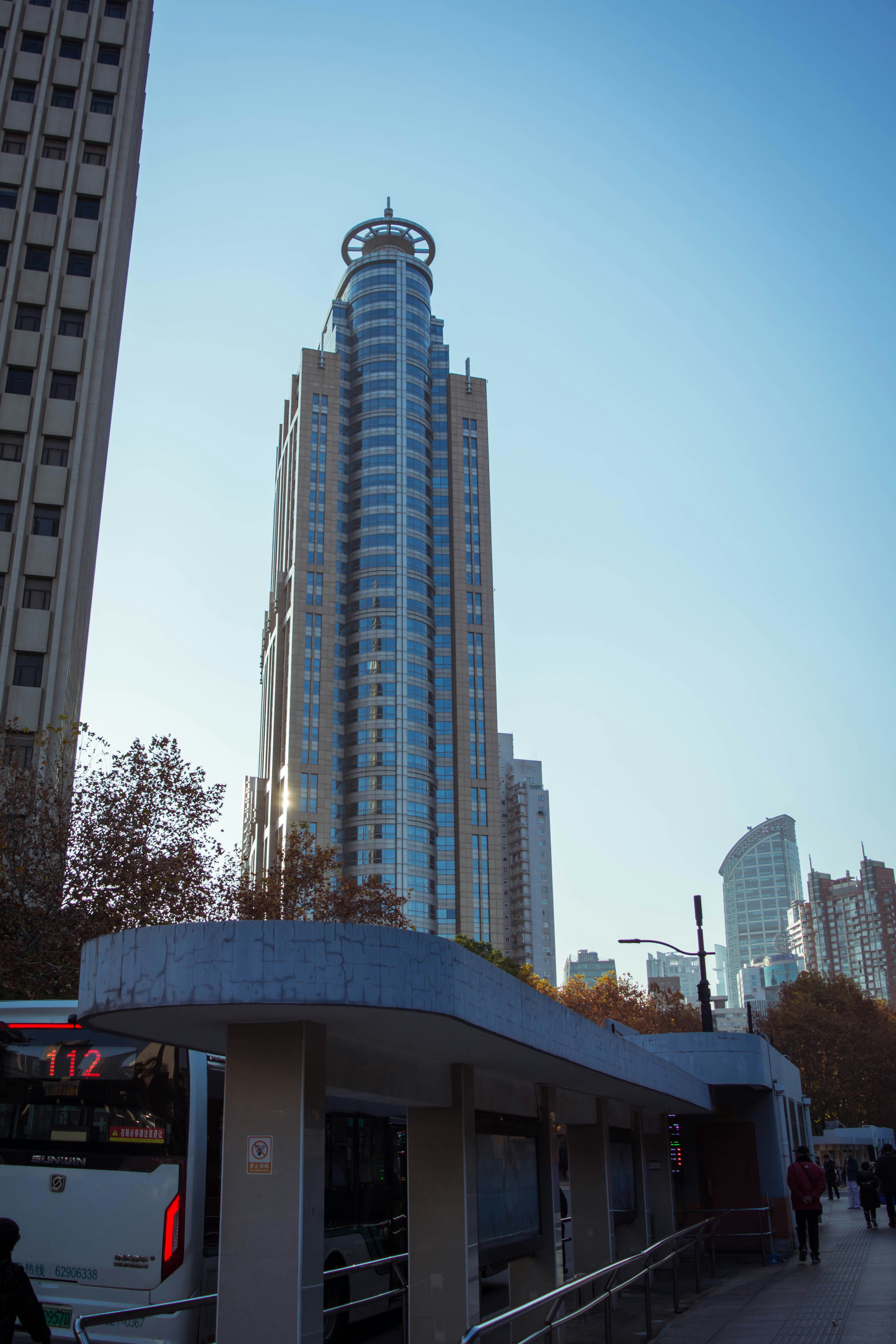 Ringed Skyward: The Cylindrical Glass Tower Above a Busy Street