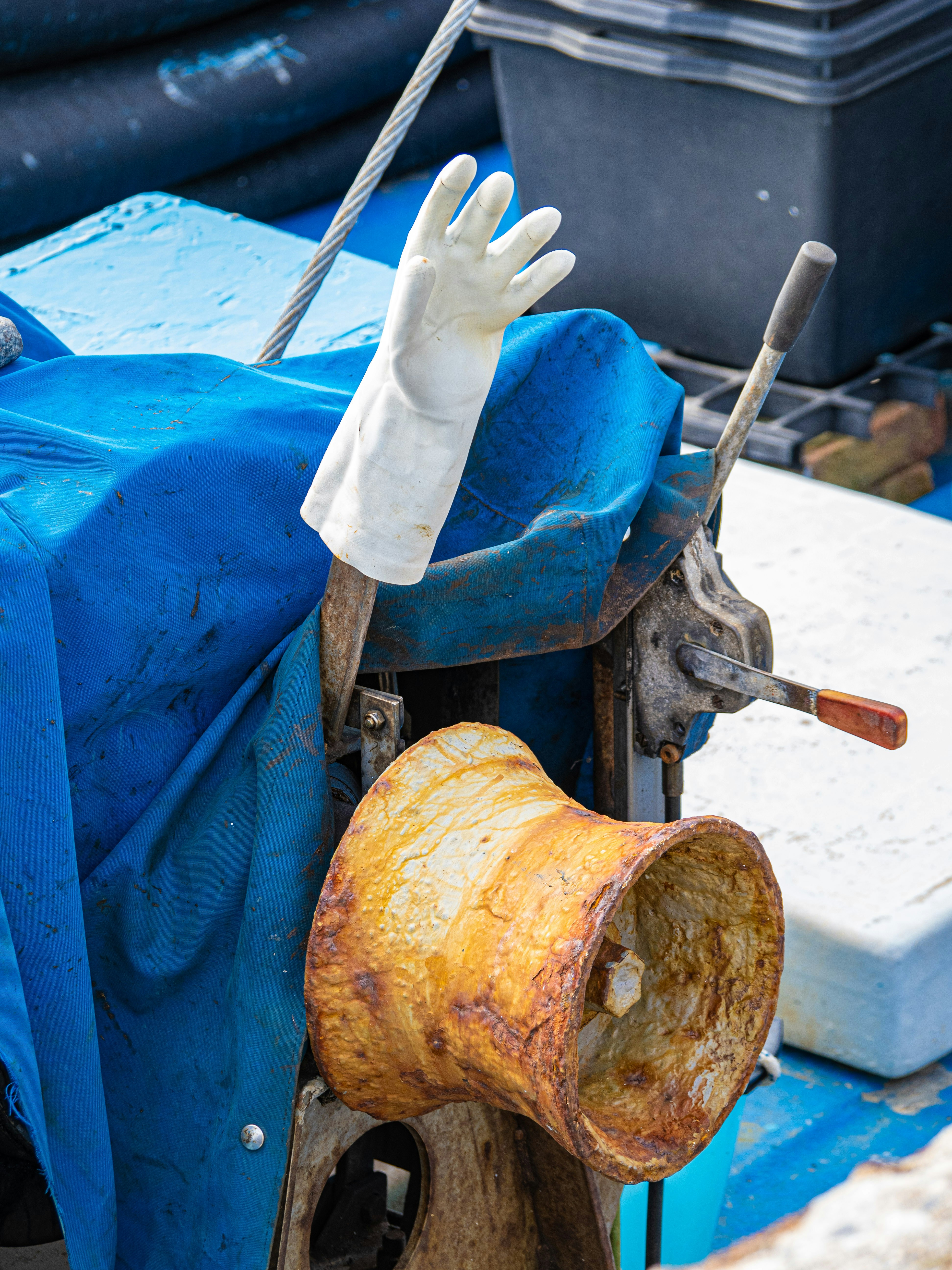 Blue tarp, white glove, and rusted gear: a maritime worksite still life