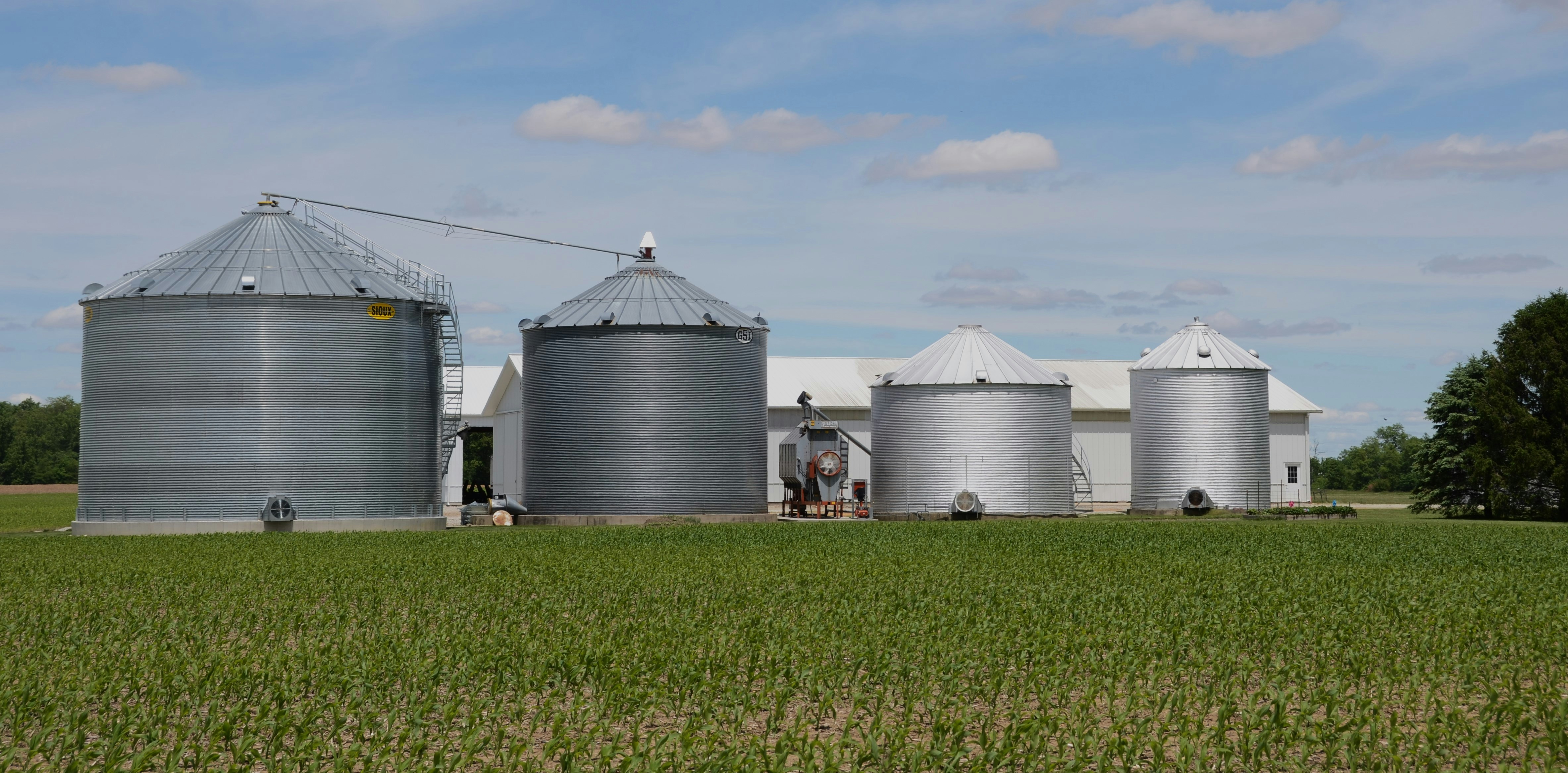 Farm silos stand in a field of crops. photo – Free Human Image on Unsplash