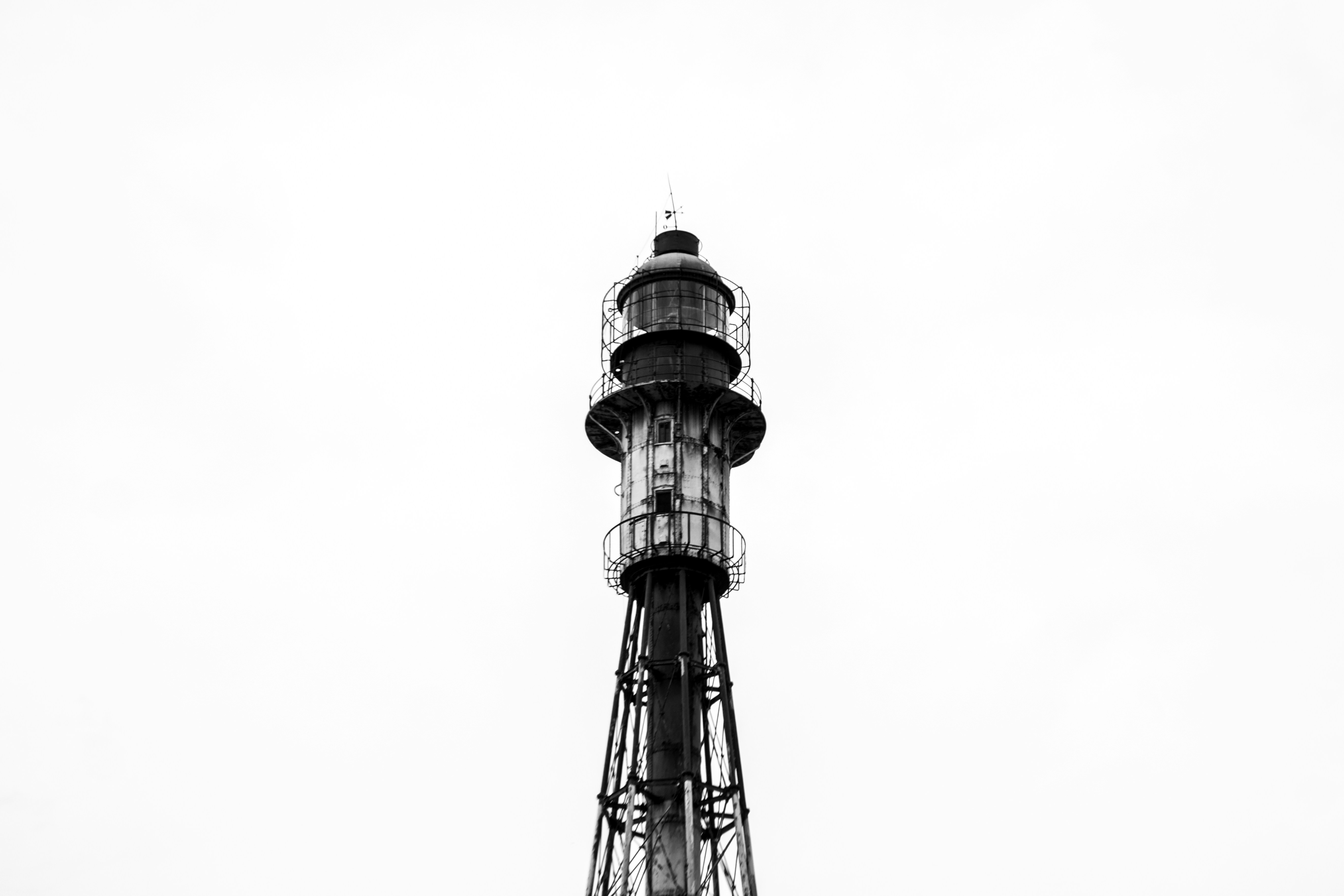 Vertical Sentinel: A solitary lighthouse against a stark white sky