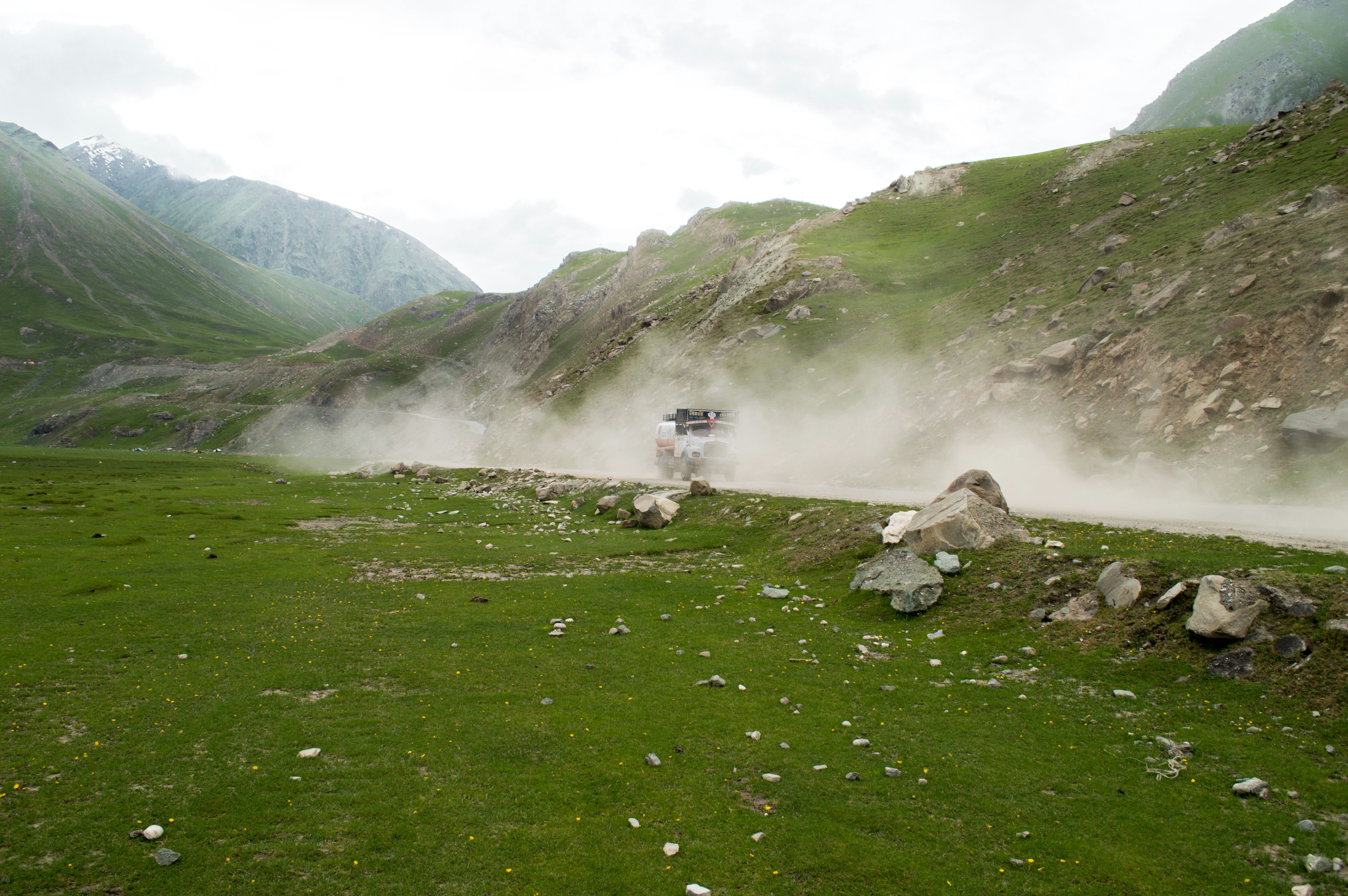 Dust Trail Through Alpine Meadow as Truck Closes the Gap