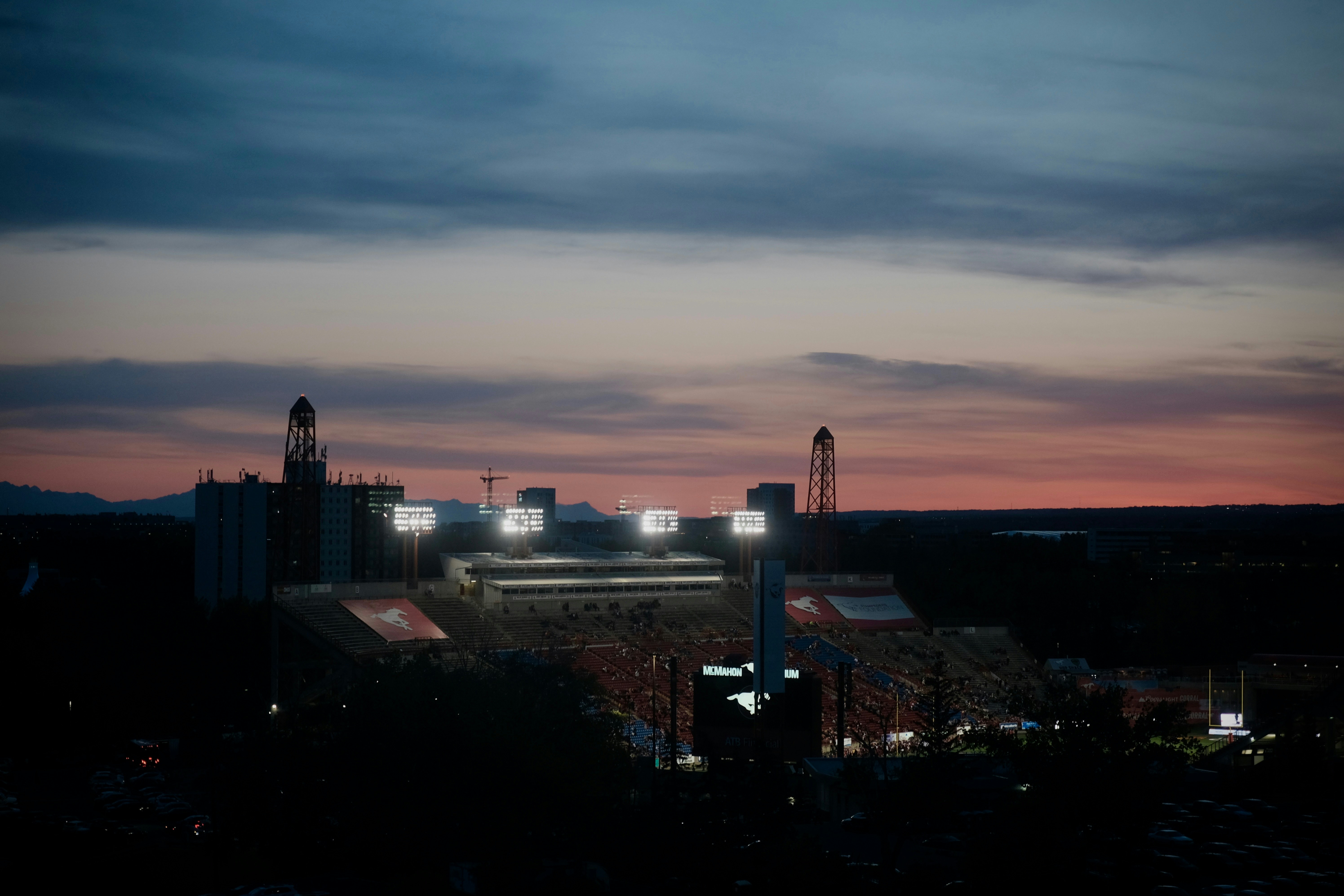 A football stadium lights up at dusk.