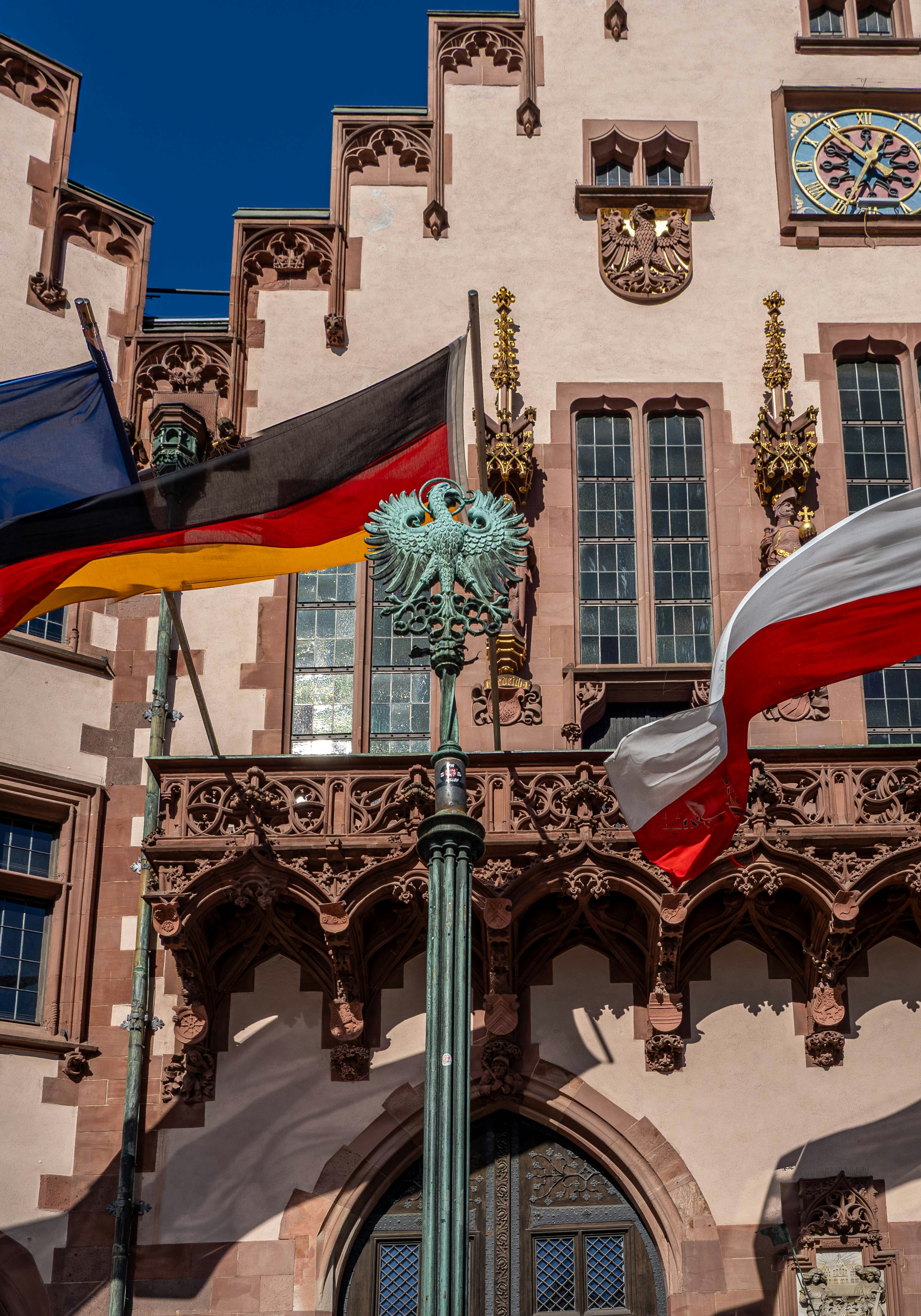 Ornate Green Lamp Framed by Flags Over a Gothic Facade