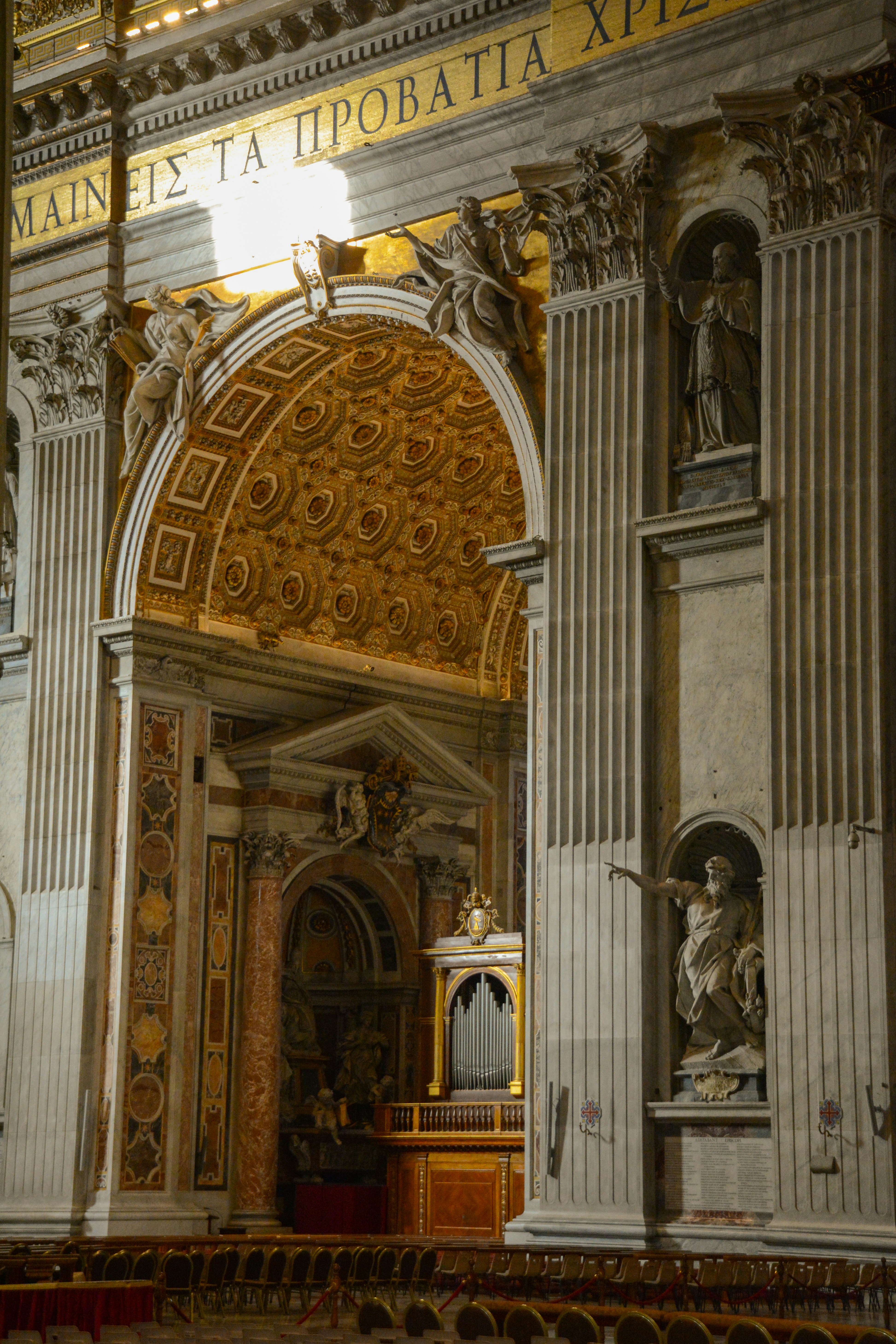 Intricate architectural details of St. Peter's Basilica featuring grand columns and ornate sculptures. The image captures the interplay of light and shadow within the sacred space.
