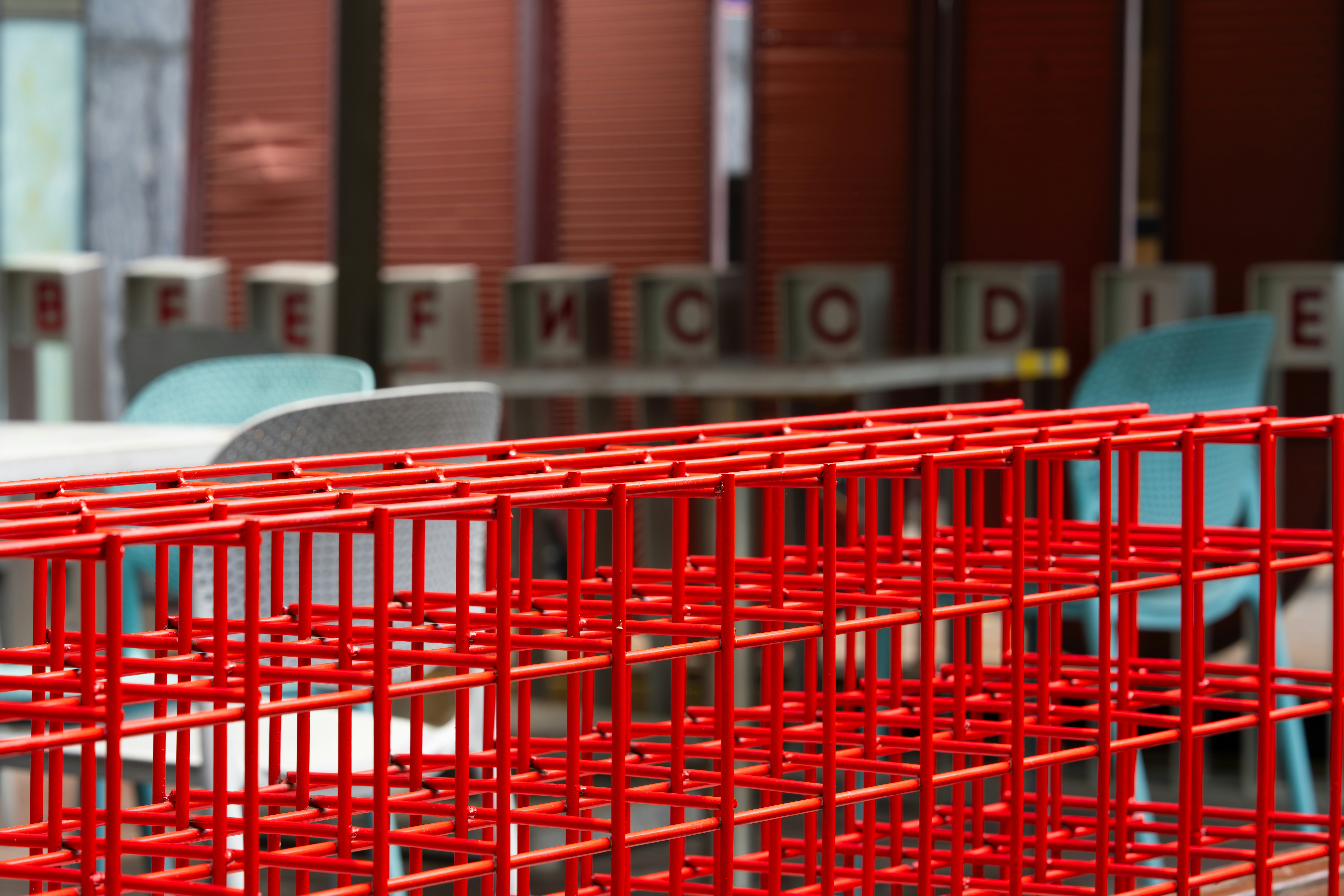 Red Cage: A Tangled Mesh of Foreground Grids with Urban Backdrop