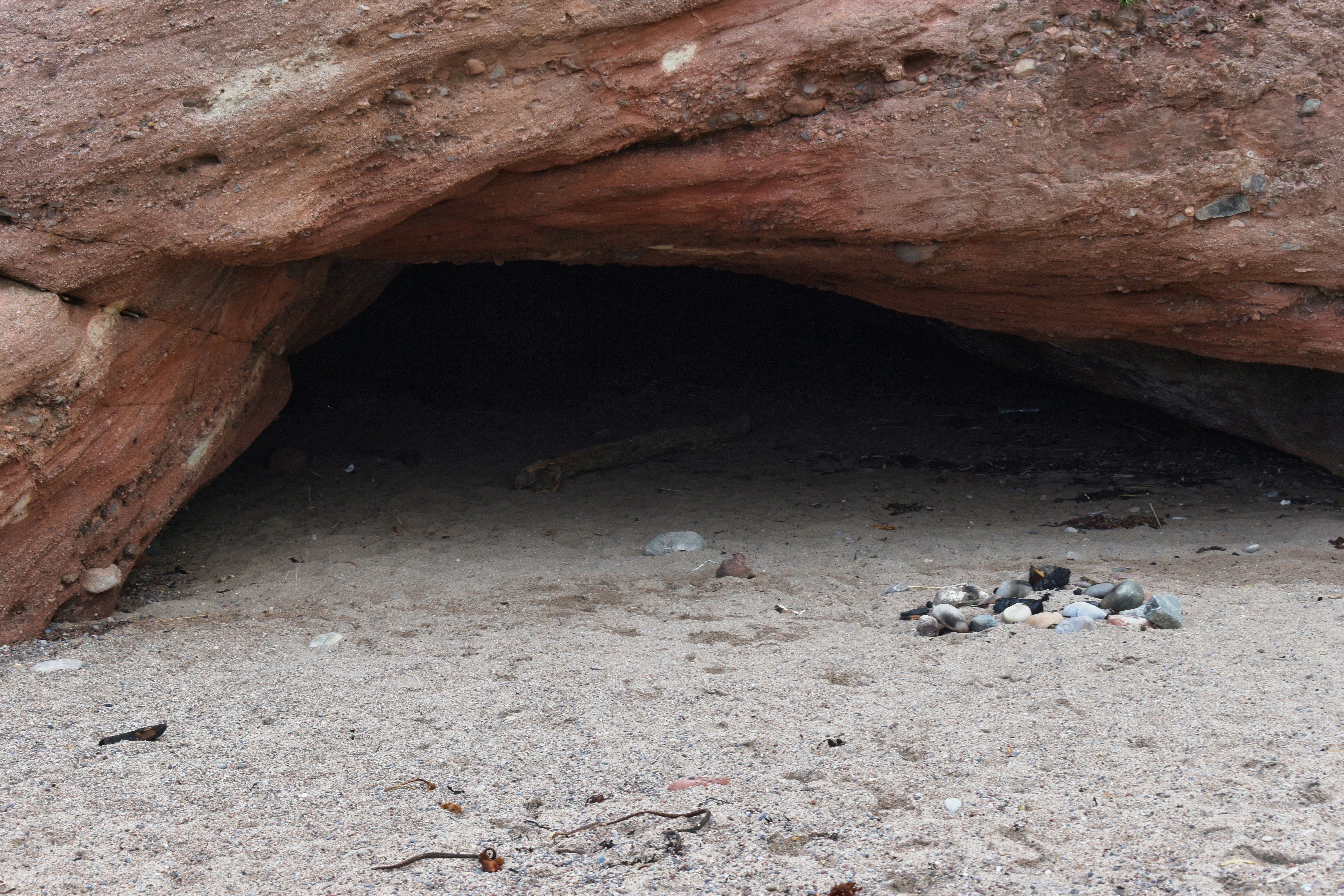 Red Rock Gate: shadowed shore cave under a coastal arch