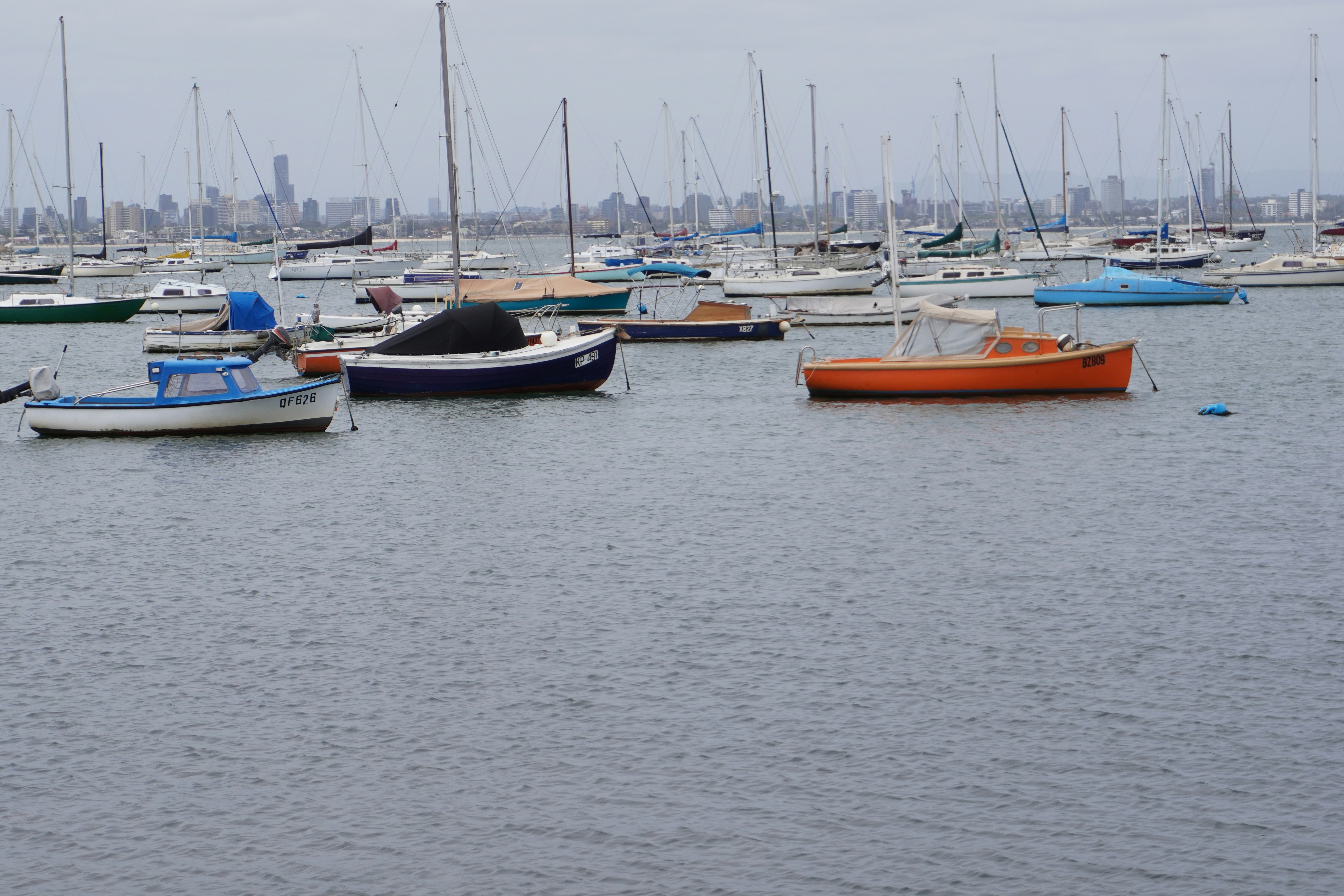 Orange Beacon in a Serene Marina: Boats and a Distant Skyline