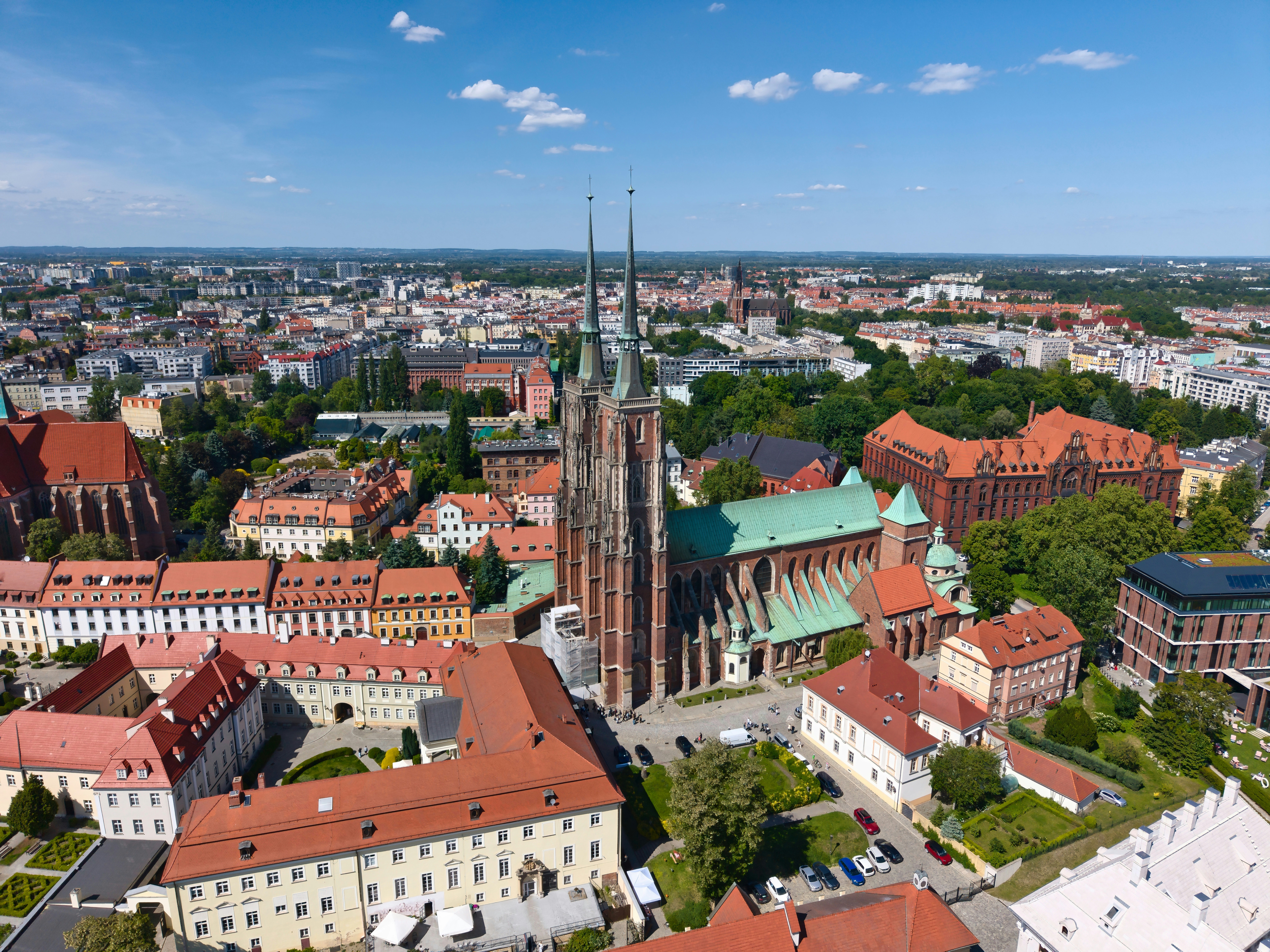 Gothic cathedral with prominent spires surrounded by a vibrant cityscape, showcasing a blend of historical and modern architecture.