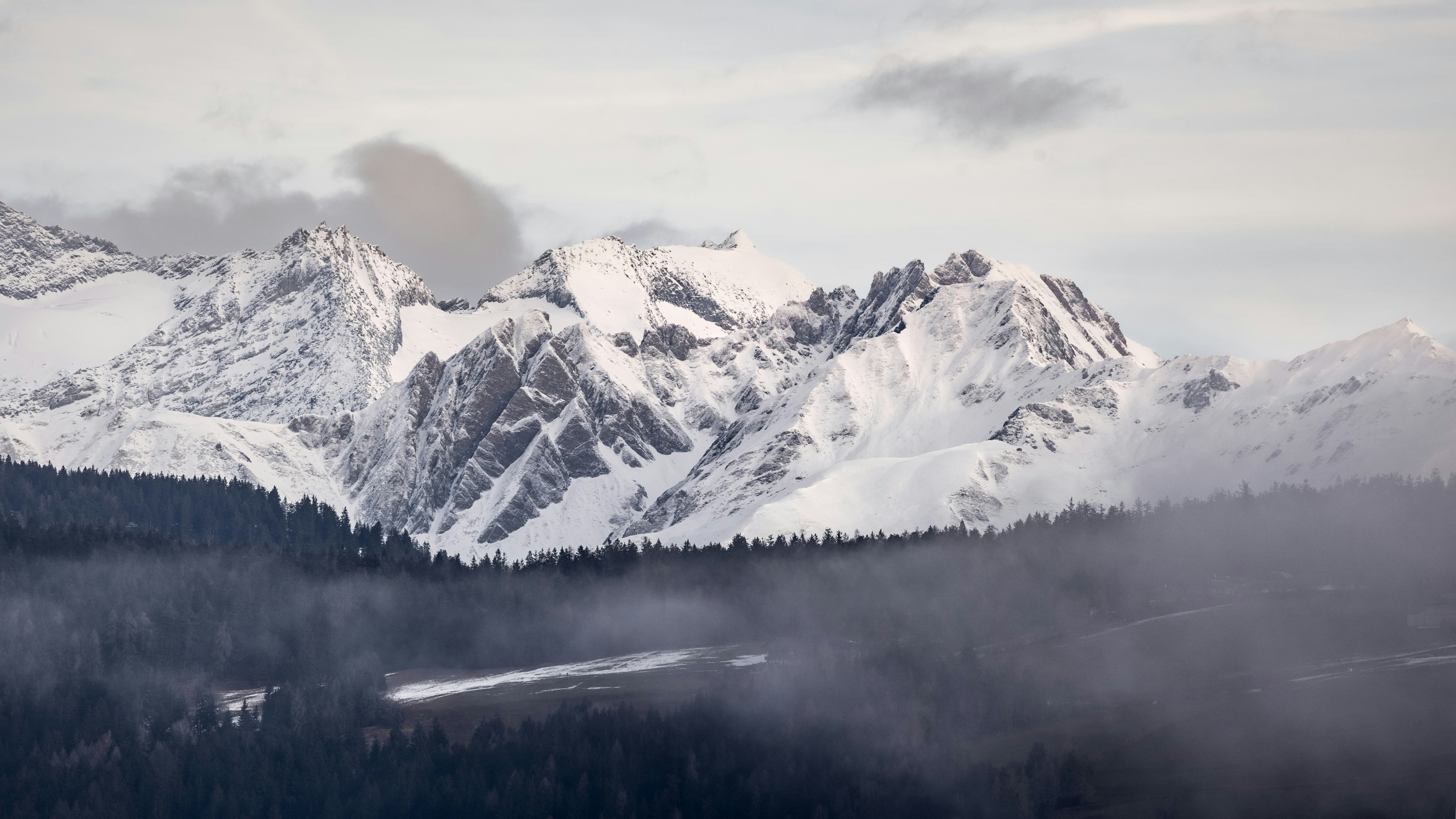 Snow-capped mountains rise above a misty forest. photo – Free Forest ...