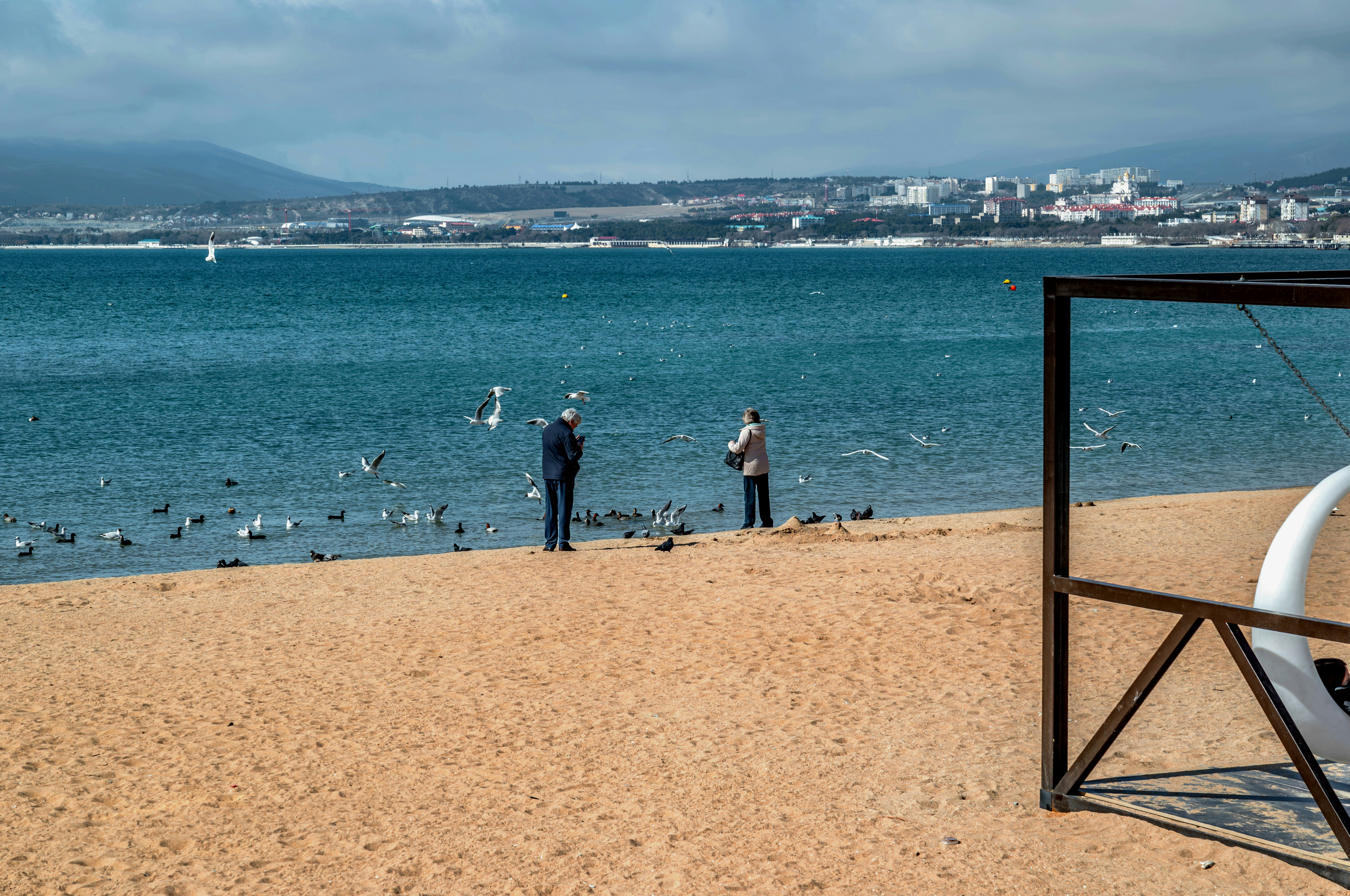 Zwei Personen stehen an einem Strand mit Blick auf das Meer. Foto ...