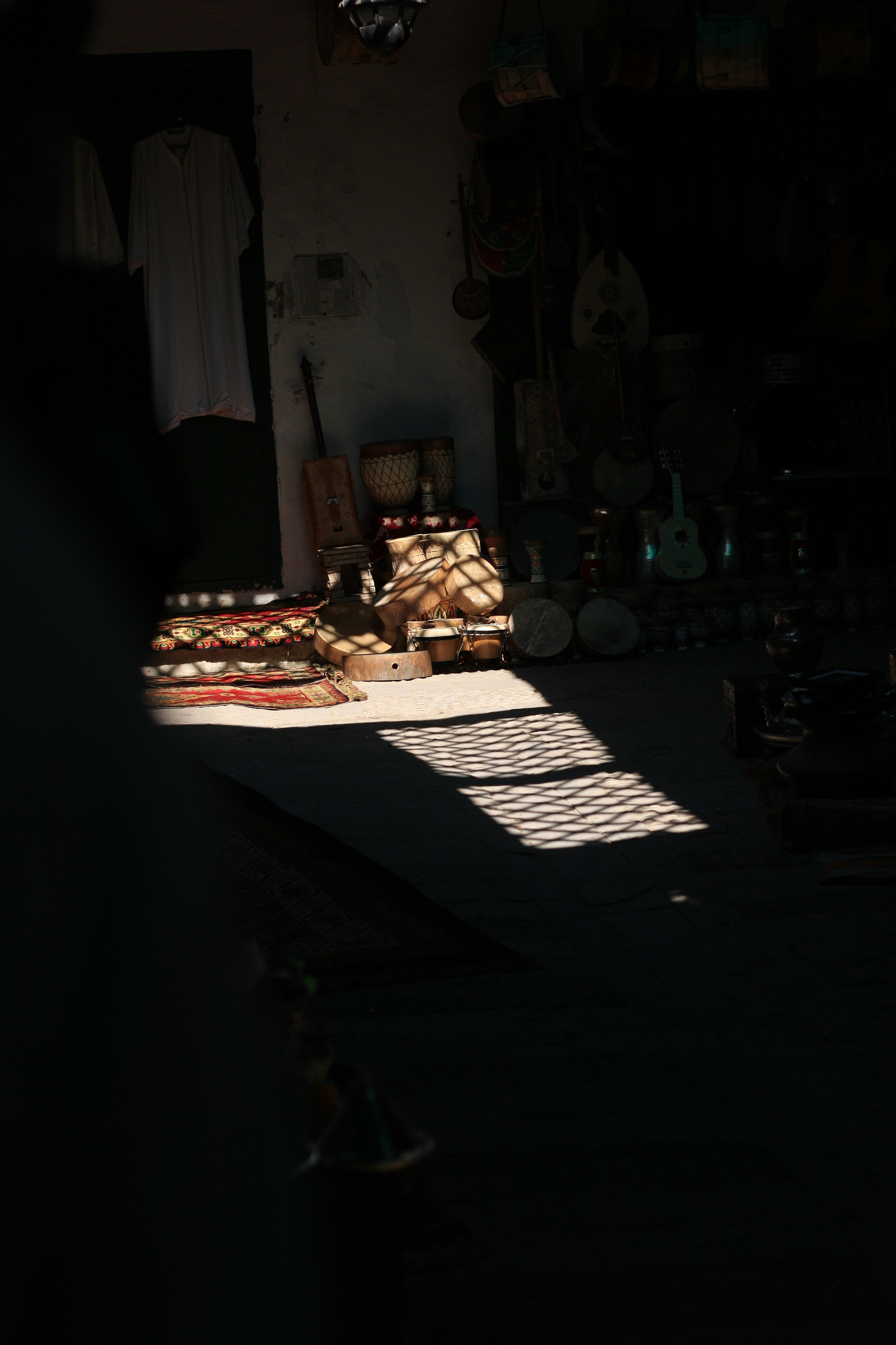 Even in the darkest corners there's always a light telling us the richest, most fascinating stories. | A dimly lit room with displayed goods.