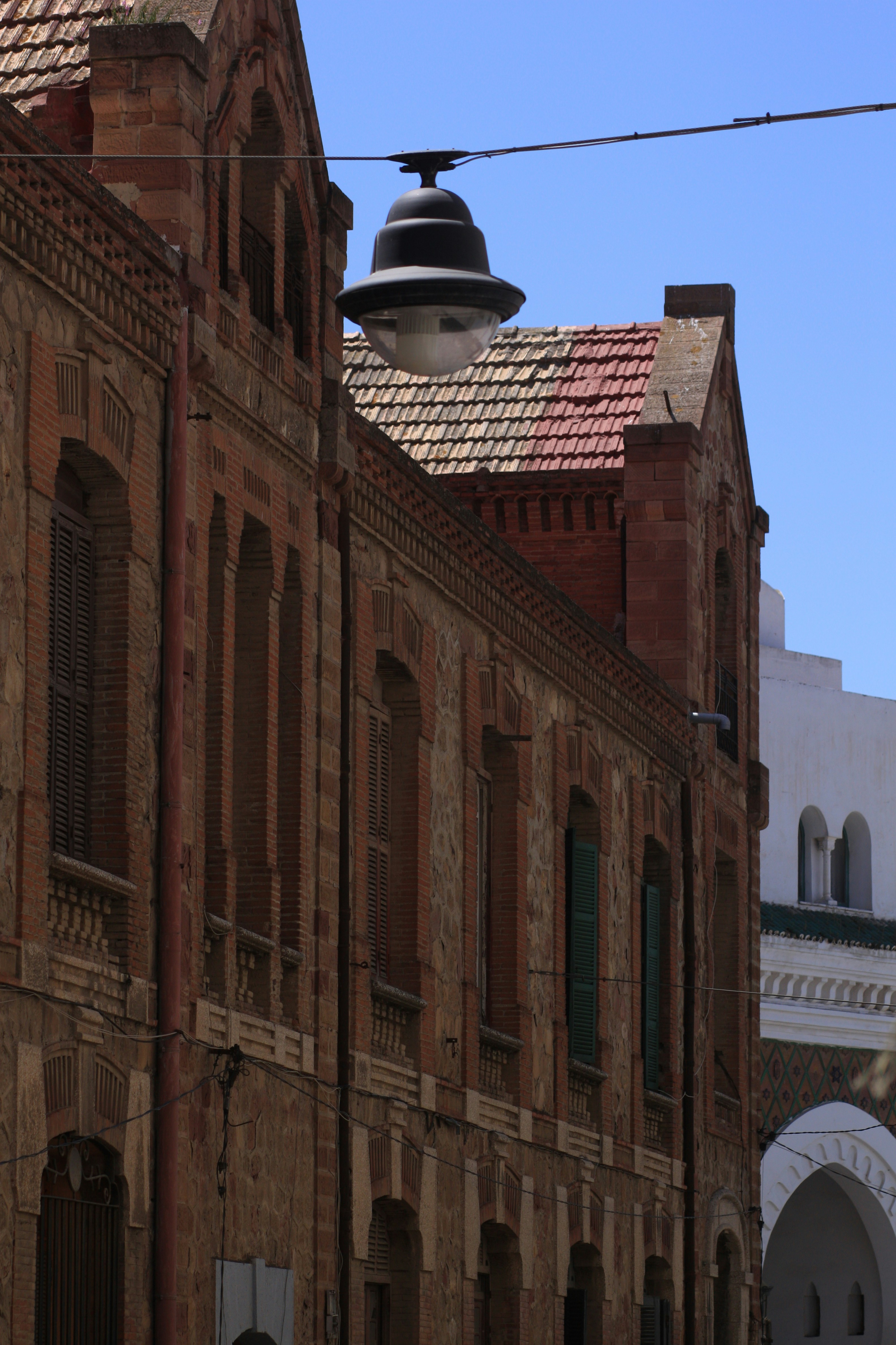 Iron Lantern Above Red-Brick Arcades Under a Clear Blue Sky