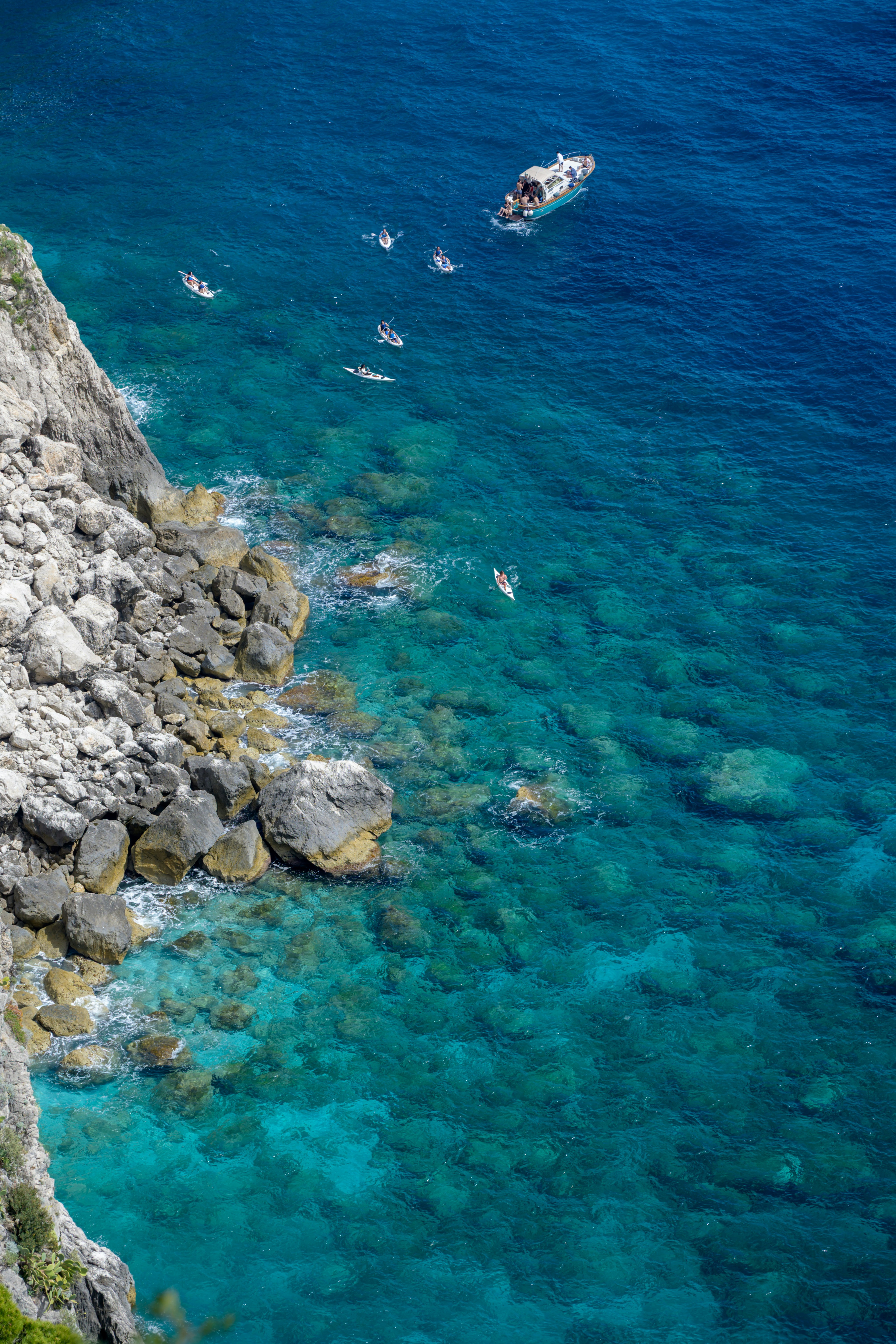A lively scene of boats navigating the turquoise waters near a rocky coastline, showcasing the vibrant marine environment.