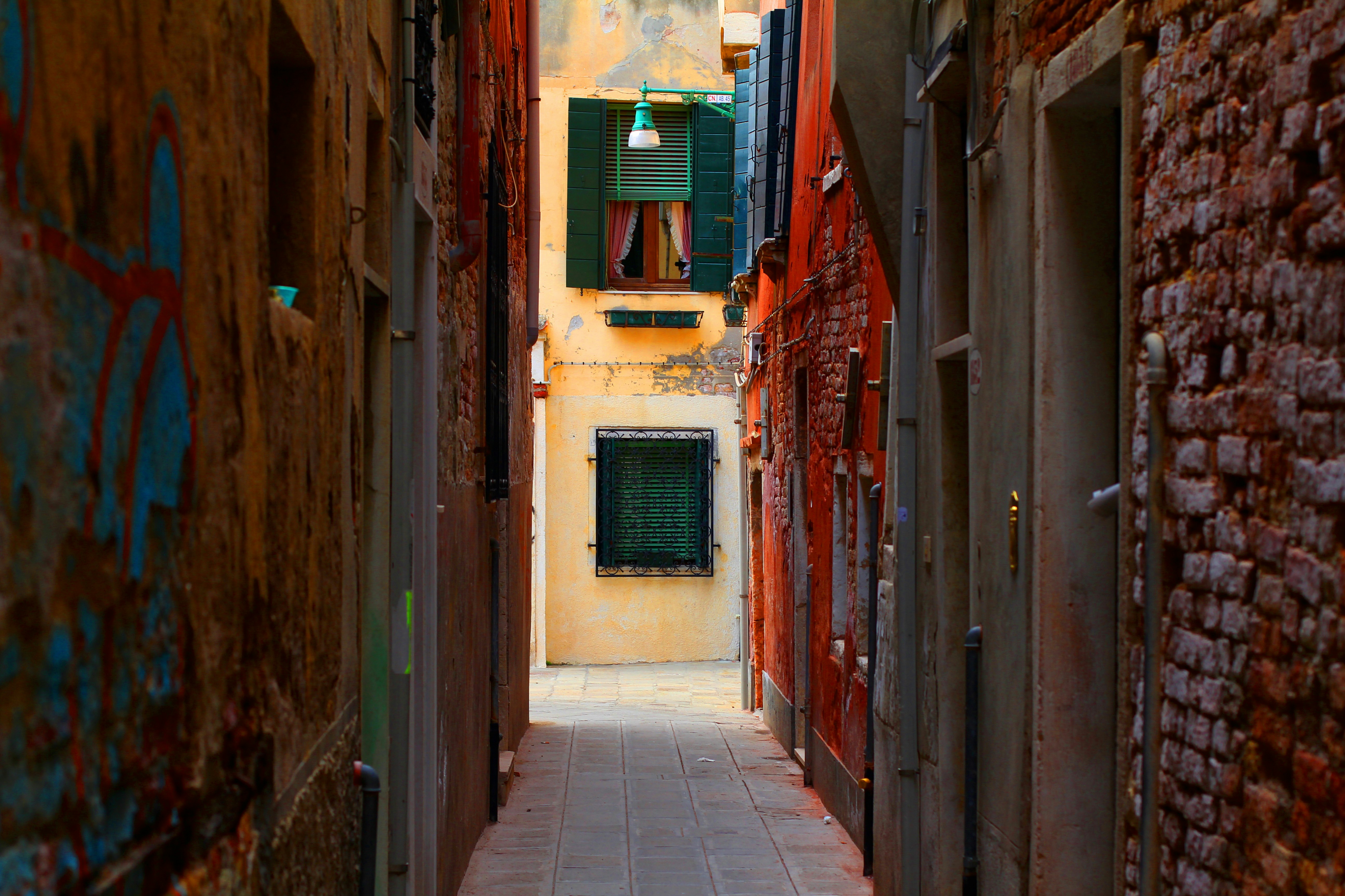 Narrow alleyway in Venice showcasing vibrant walls and a contrasting yellow building at the end.