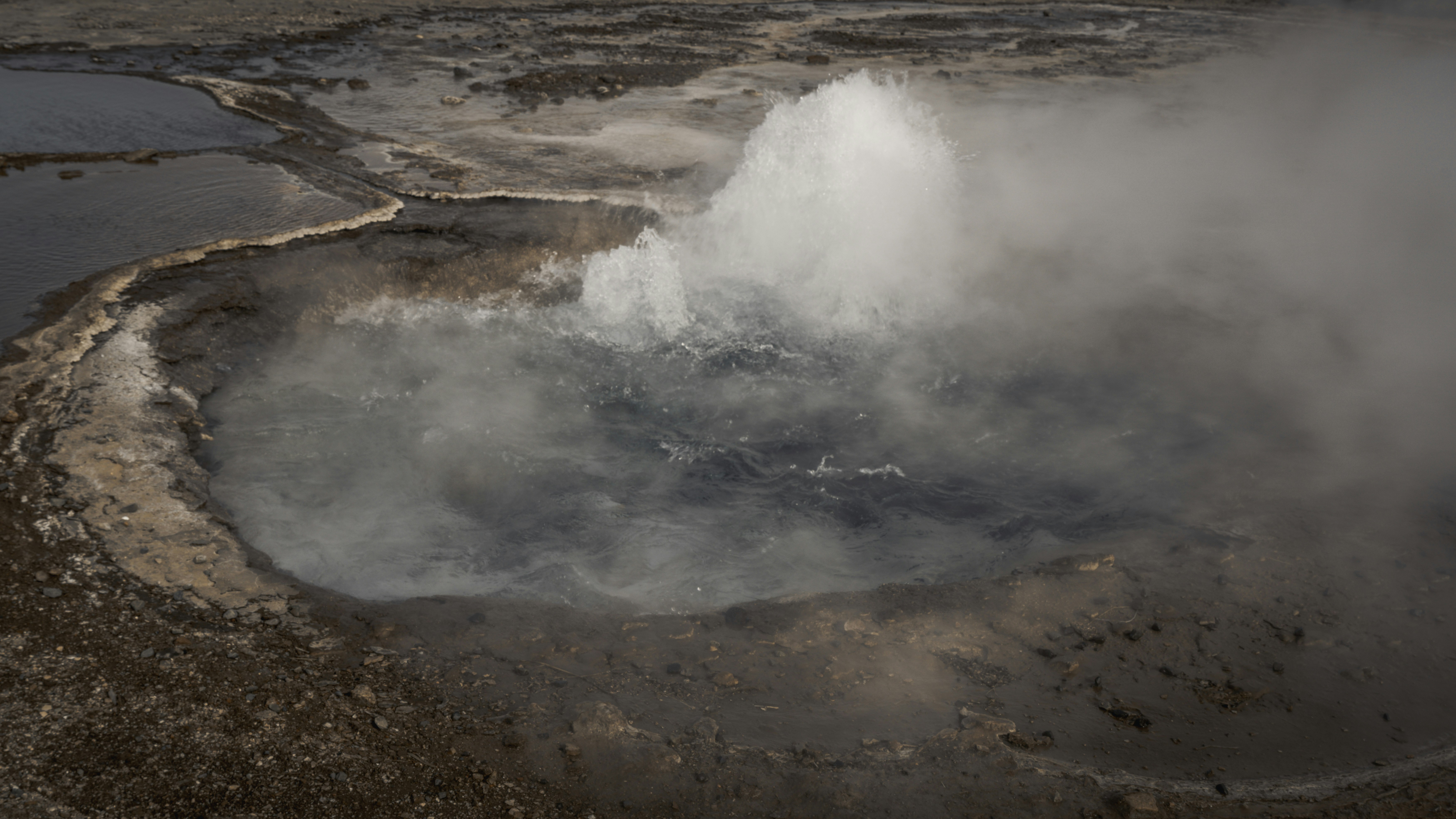 A geyser erupts with steam and hot water.